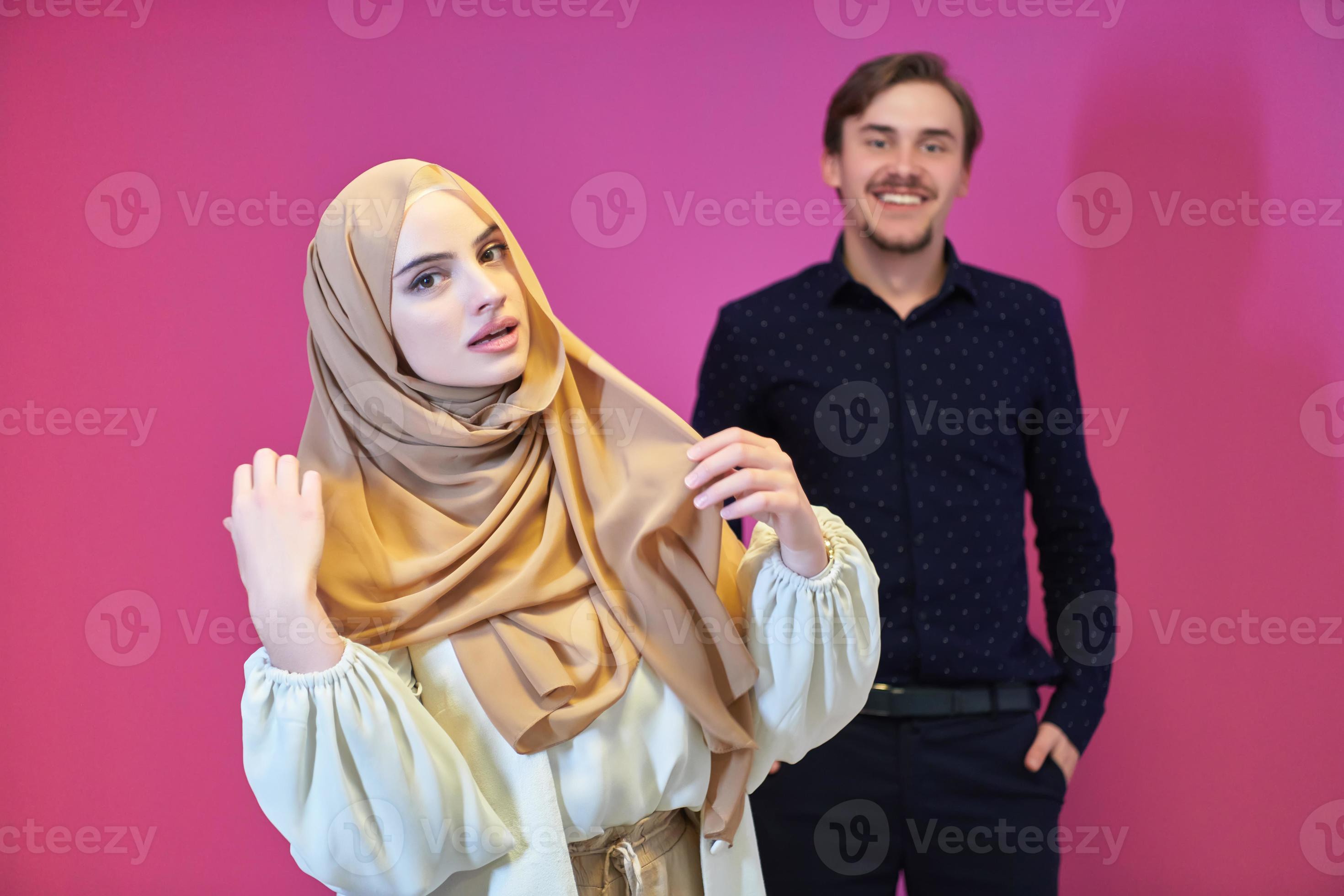 Portrait of happy young muslim couple standing isolated on pink ...