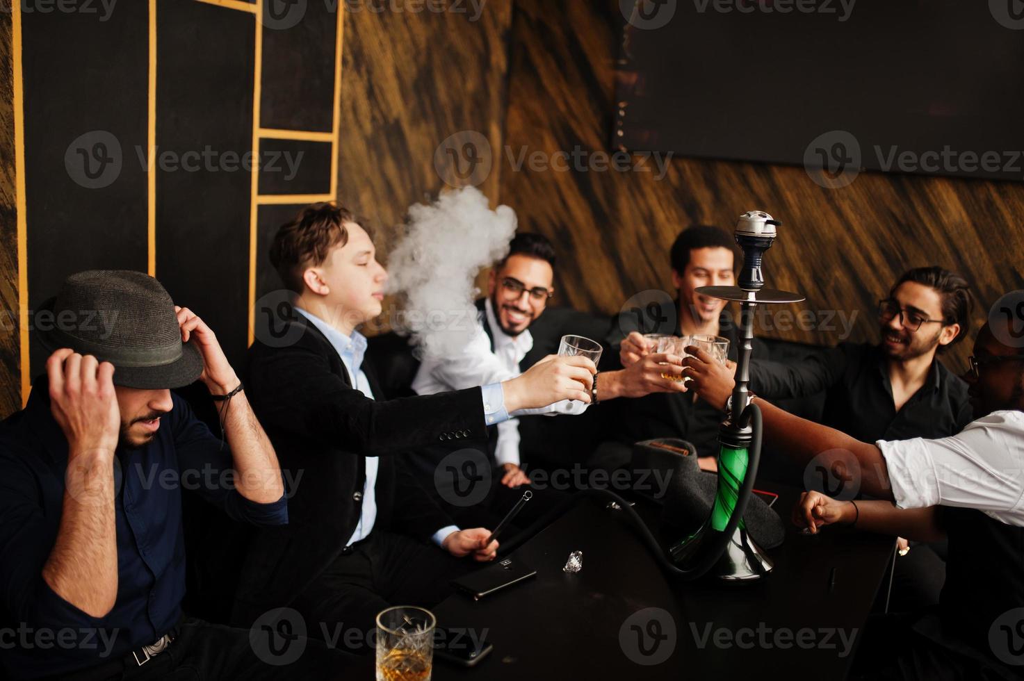 Group of handsome retro well-dressed man gangsters spend time at club, smoking hookah ...