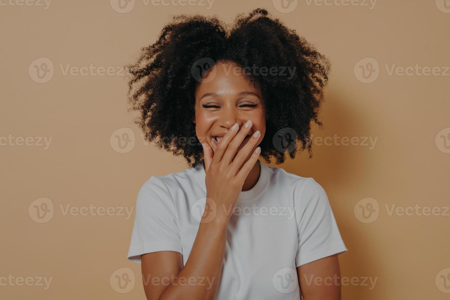 Beautiful dark skinned millennial woman covering her mouth with hand ...