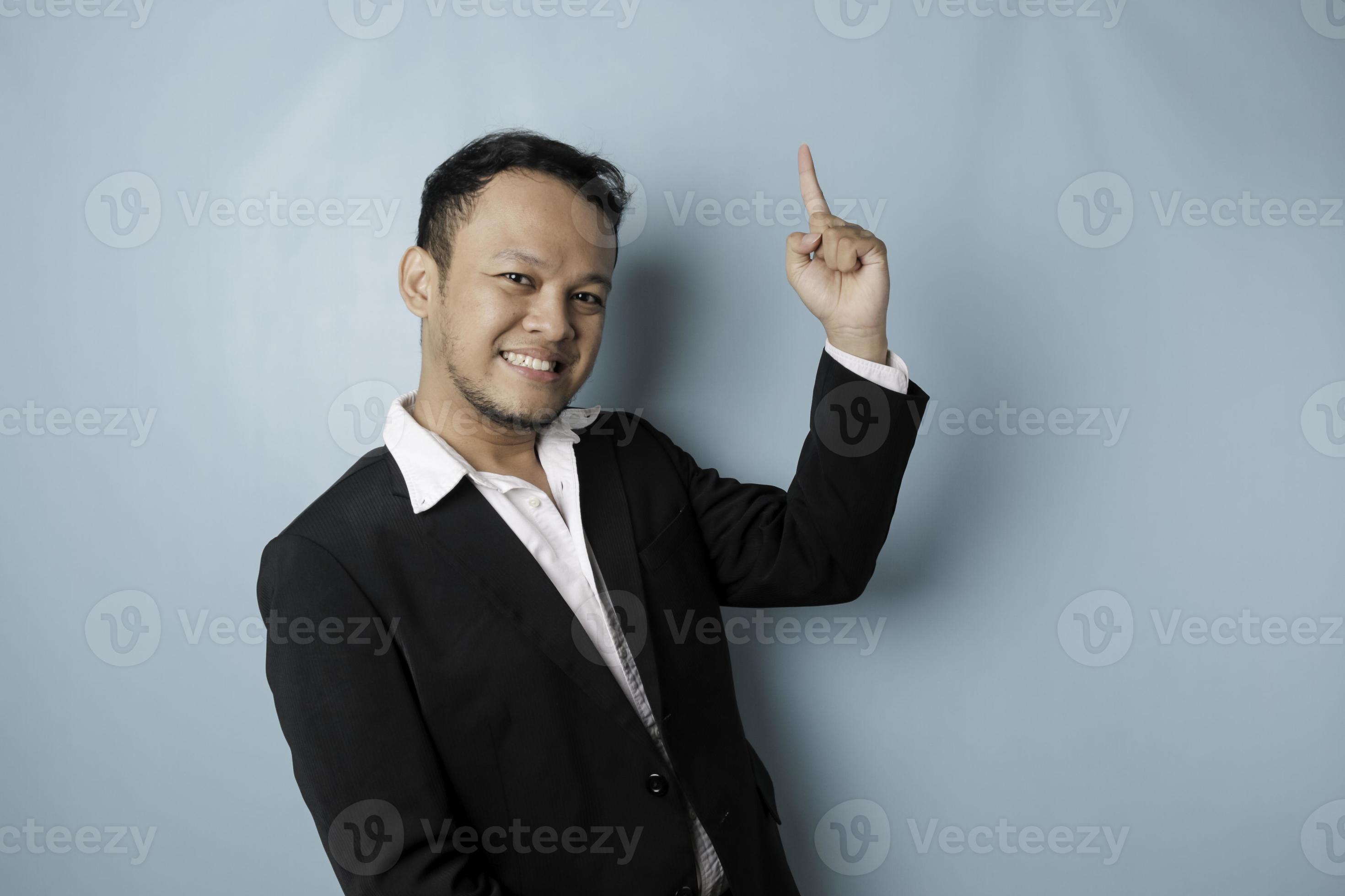 Excited Asian man wearing suit pointing at the copy space upside him ...