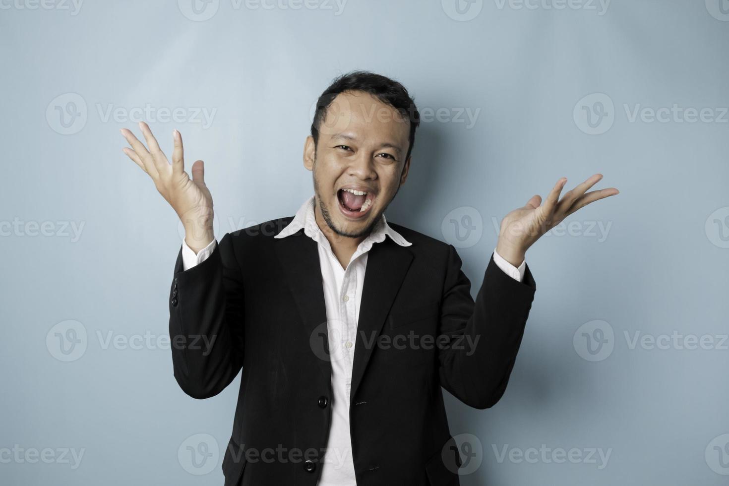 Excited Asian man wearing suit pointing at the copy space upside him ...