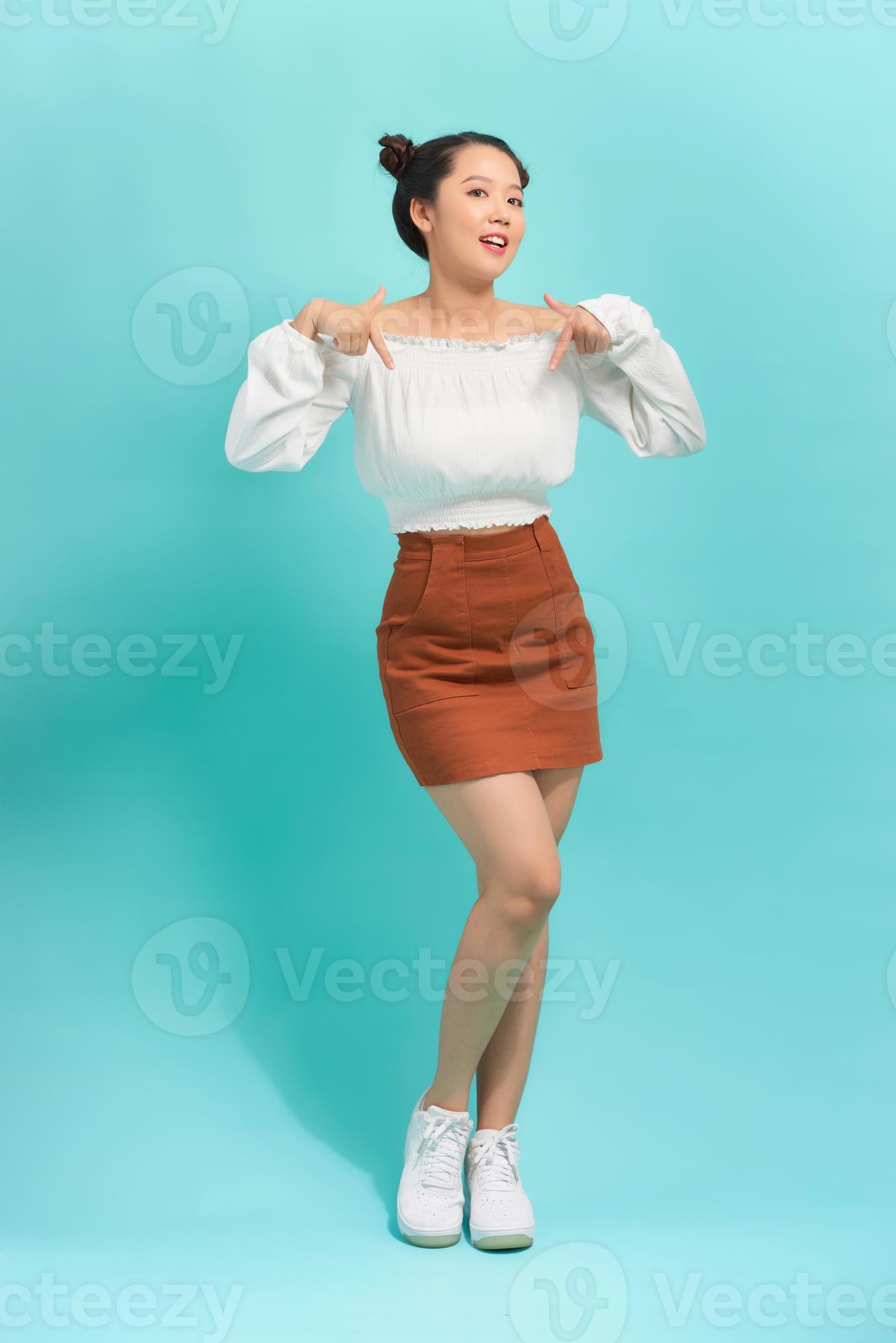 Young asian girl wearing casual clothes pointing down with fingers showing advertisement ...