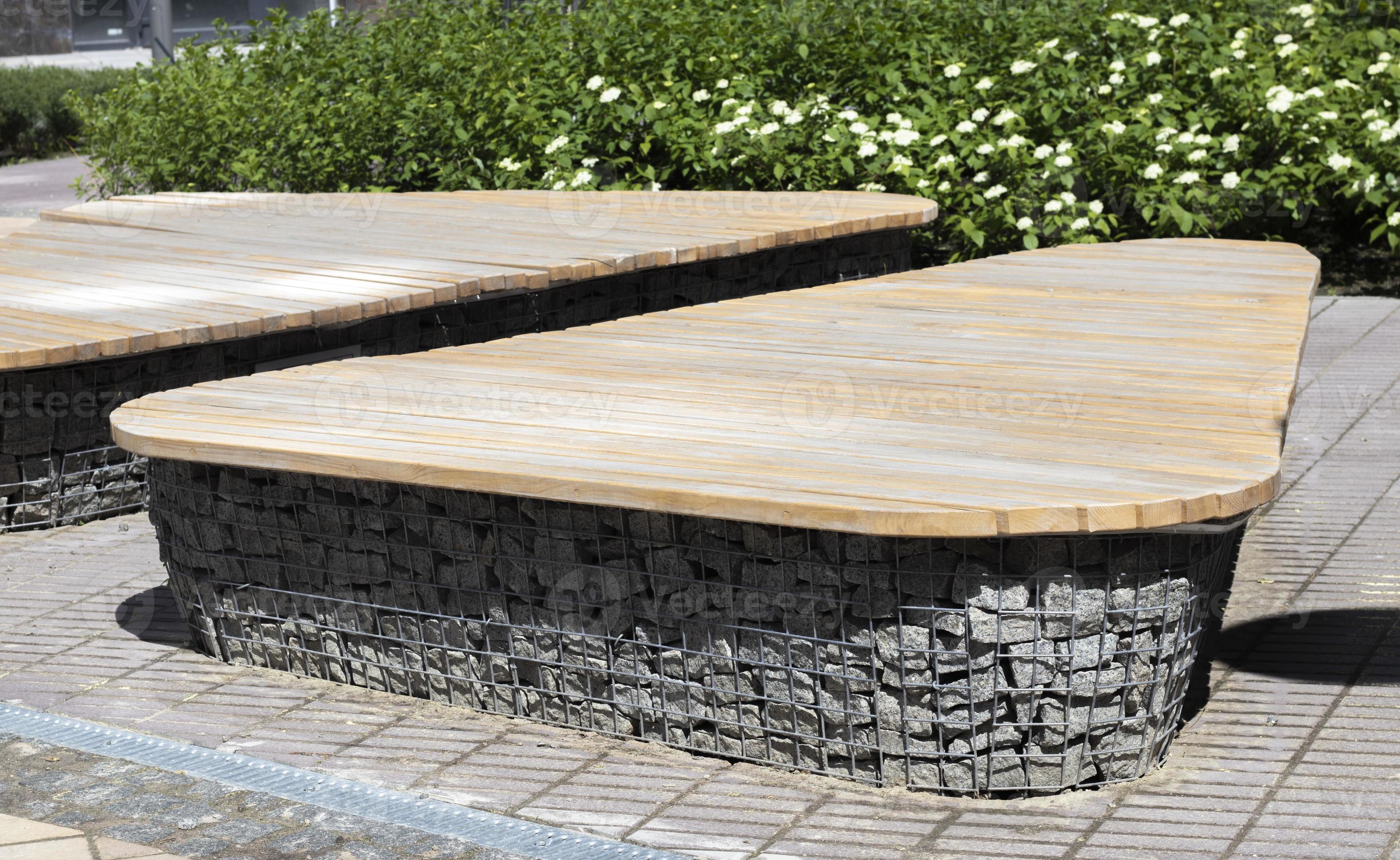 Wooden benches from gabion baskets with stones inside. Wood mounted on gabions. Benches of ...