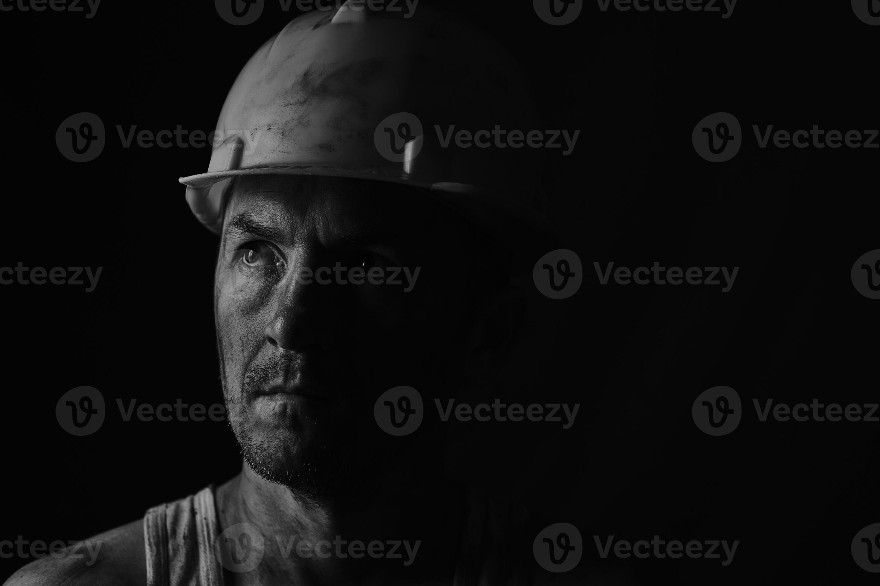 Dirty face of coal miner on a black background. Head of tired mine worker in a hard hat. Black ...