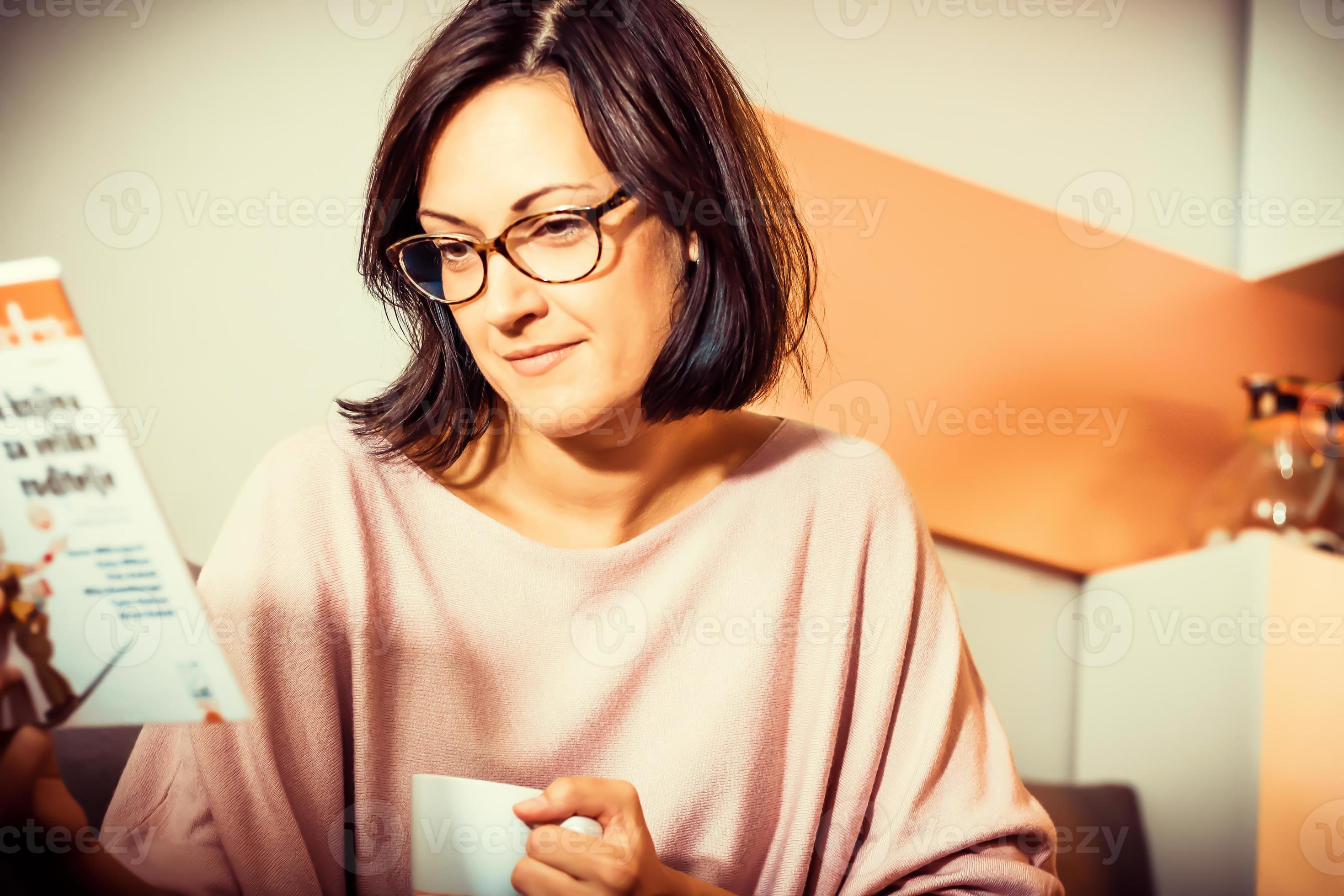 Smiling Woman Drinking Coffee While Reading Book At Home 11401039