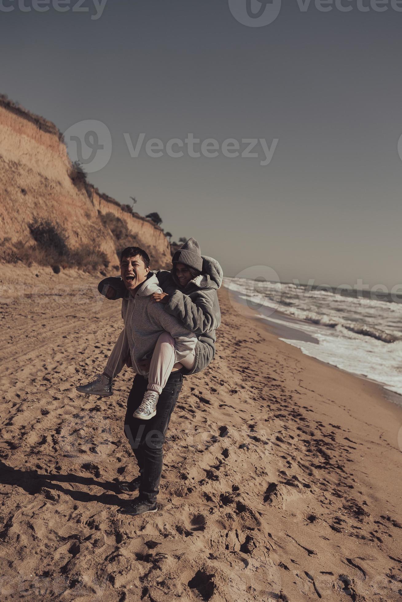 Man Carries His Girlfriend On Back Couple Having Fun On The Seashore