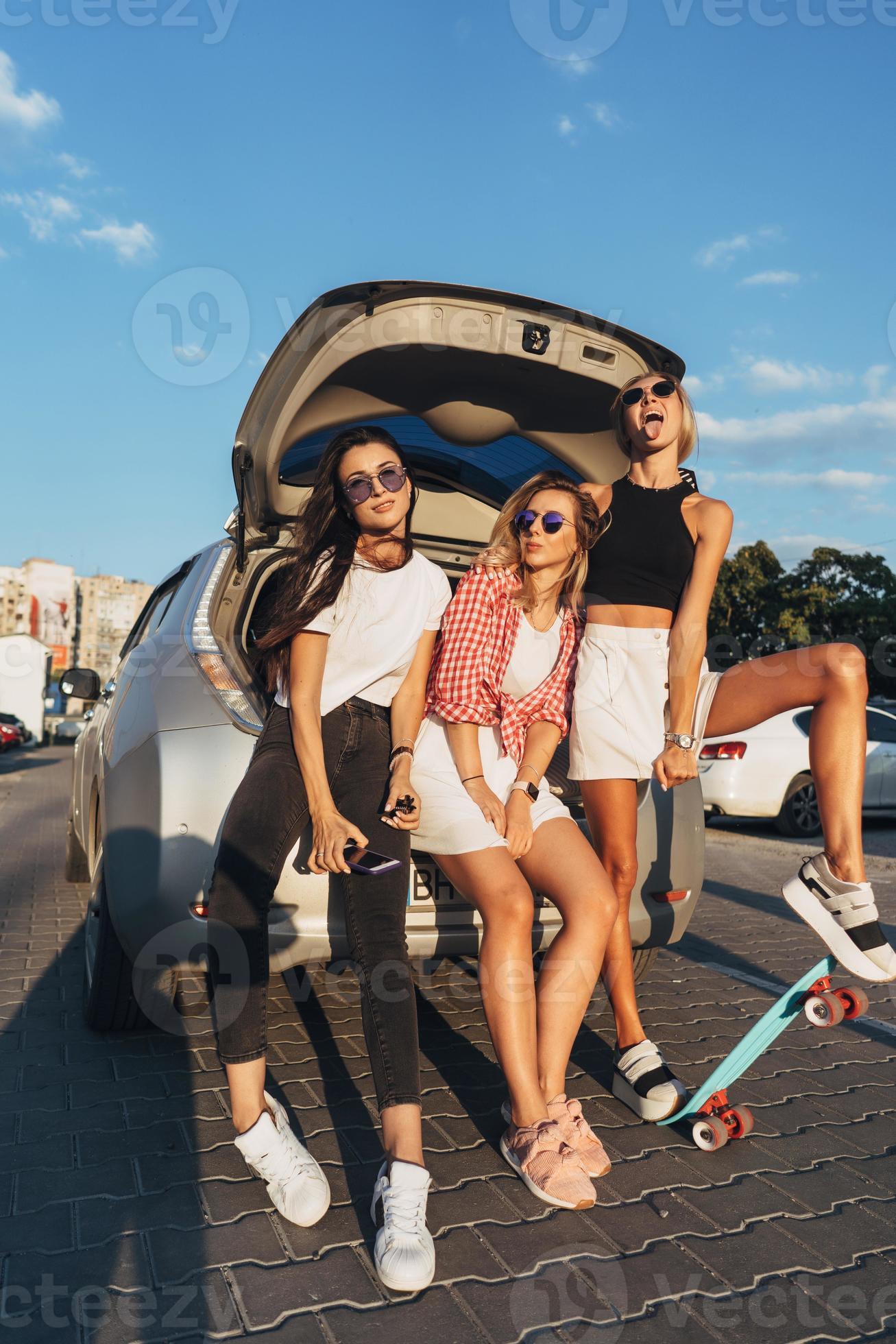 Three young woman posing for the camera the car park. 11532250 Stock ...