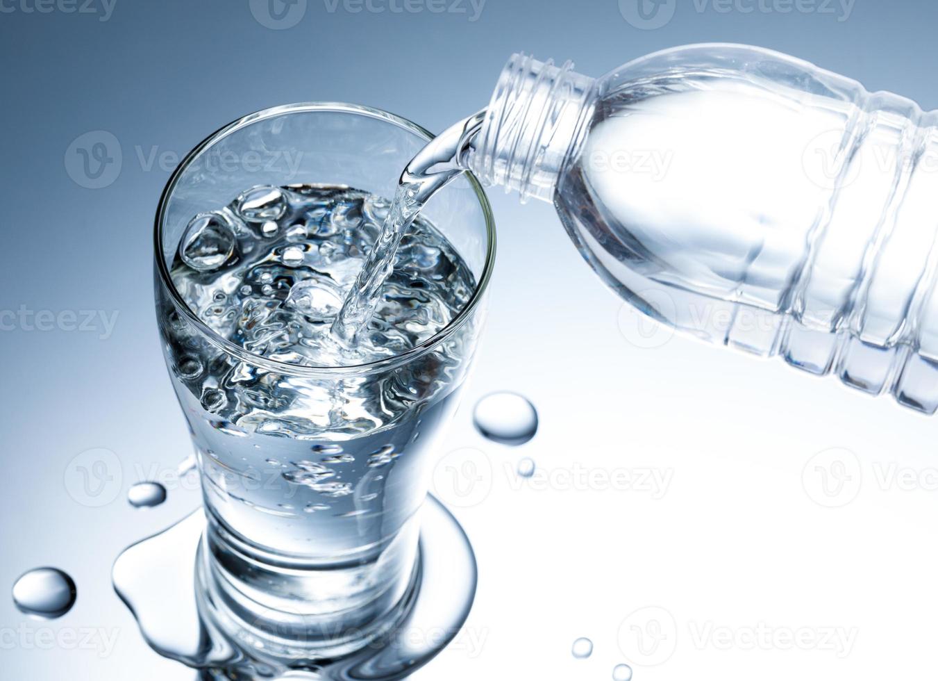Pouring fresh pure water from bottle into a glass on the table with water drops, Healthcare and ...
