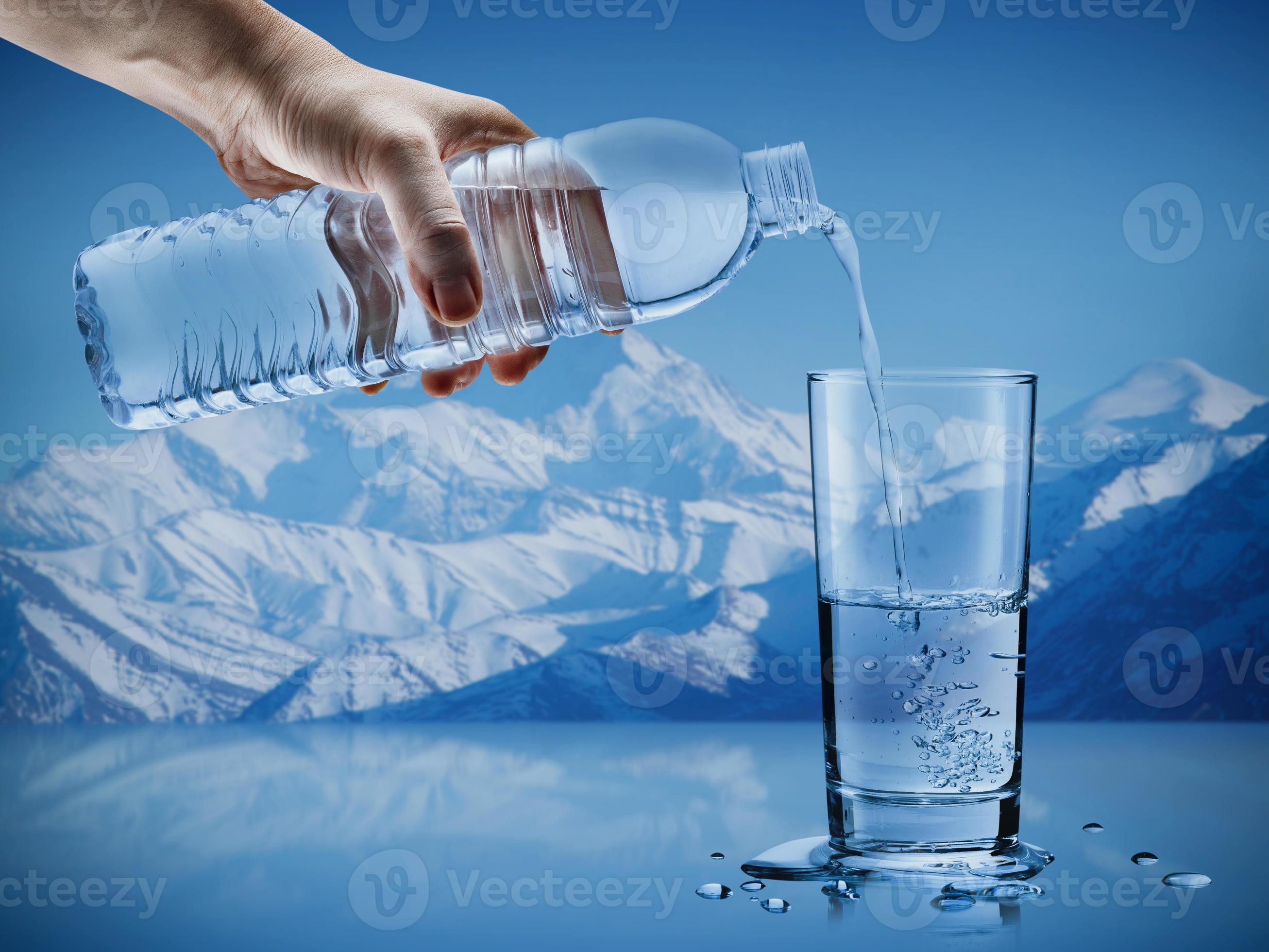 Hand pouring mineral water from bottle into a glass with water drops in the iceberg background ...
