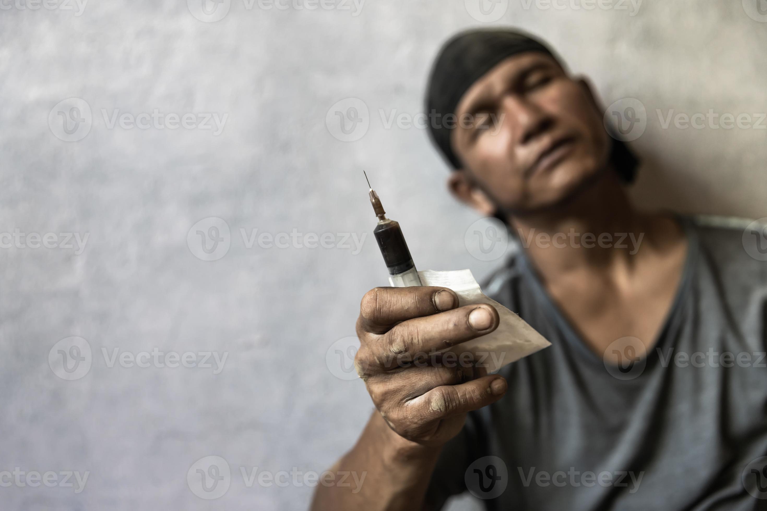The concept of anti drugs. A man is a drug addict with a syringe using drugs lying on the floor ...