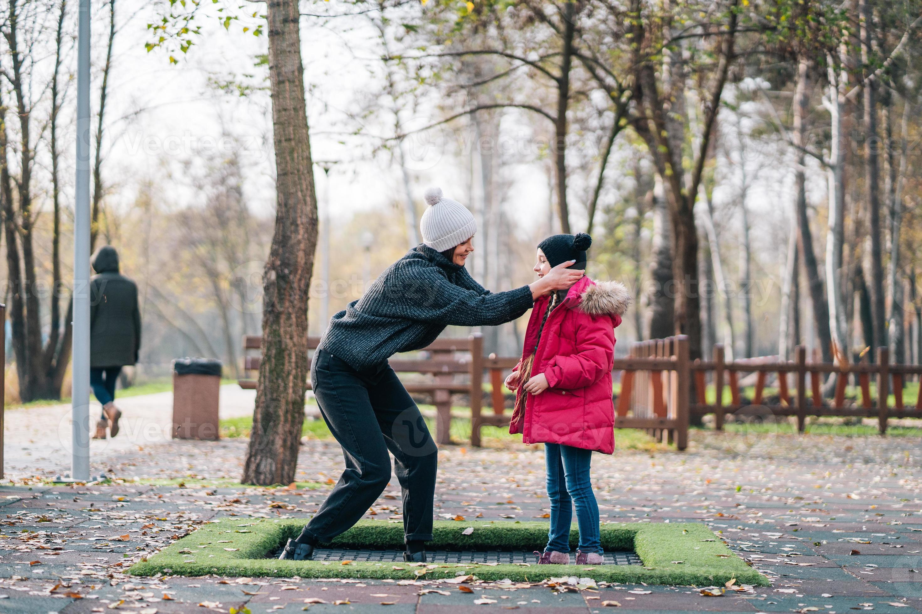 Mom And Her Daughter Jumping Together On Trampoline In Autumn Park