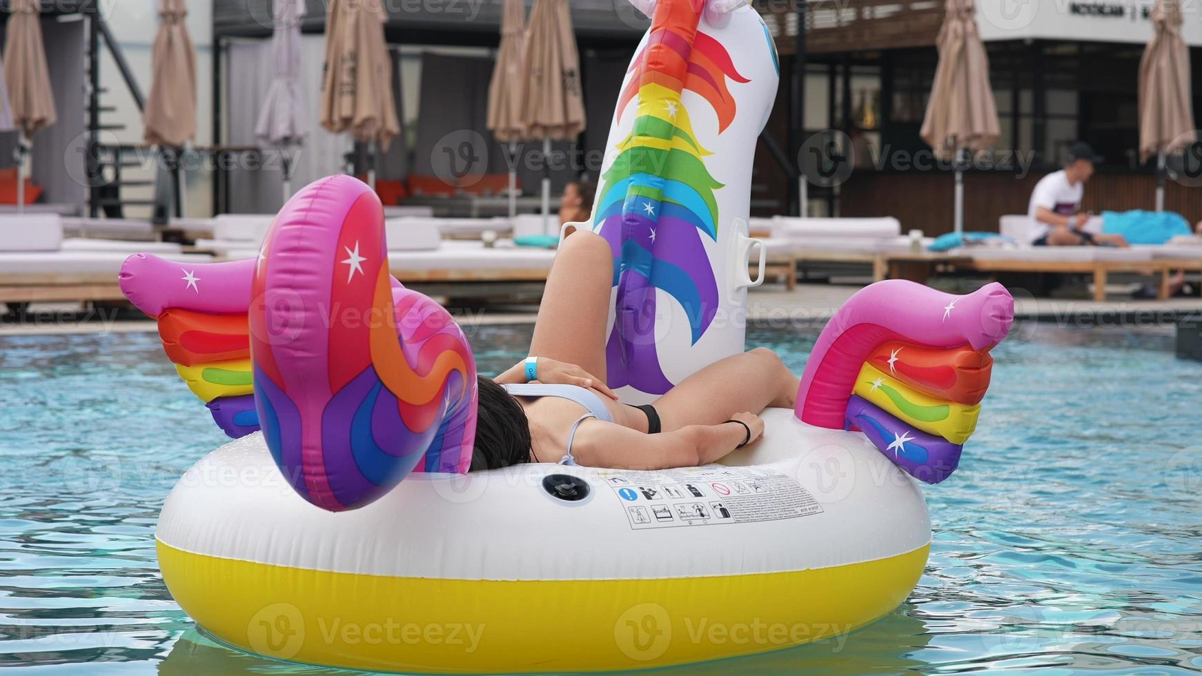 Woman In Bikini In Inflatable Unicorn Toy Mattress Float In Pool