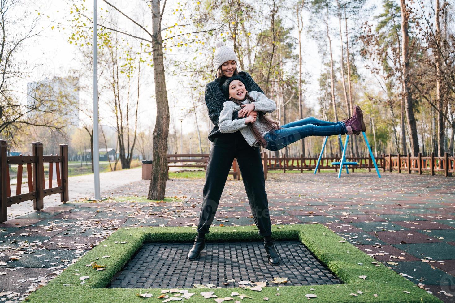 Mom And Her Daughter Jumping Together On Trampoline In Autumn Park