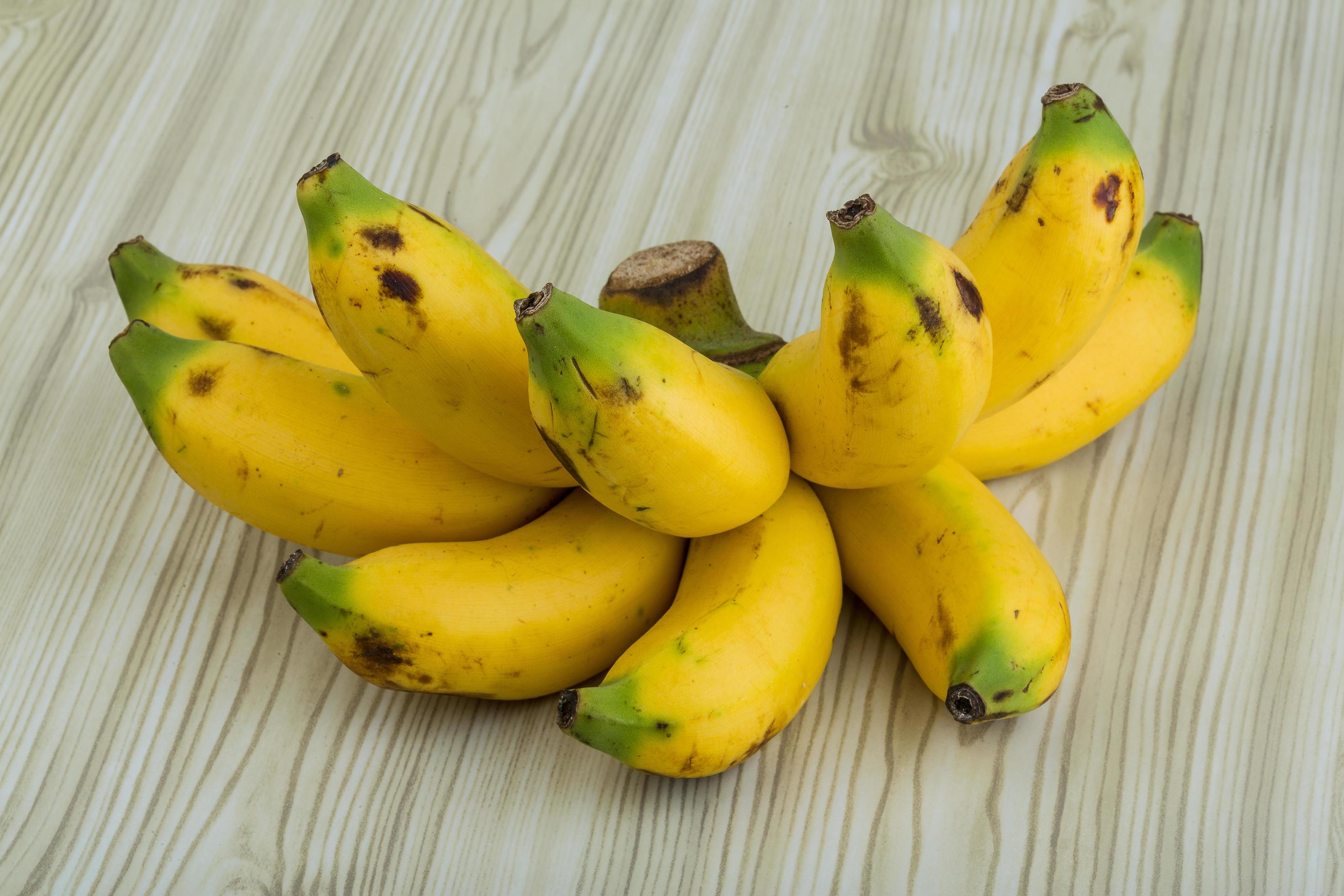 Baby banana on wooden background 12060965 Stock Photo at Vecteezy