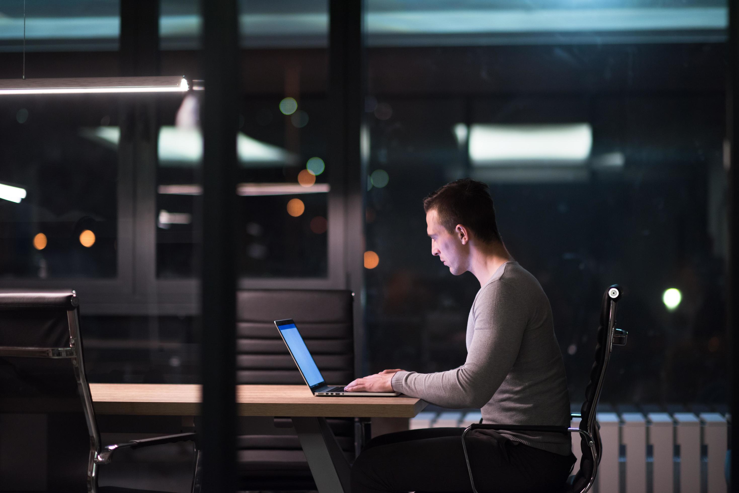 man working on laptop in dark office 12432257 Stock Photo at Vecteezy