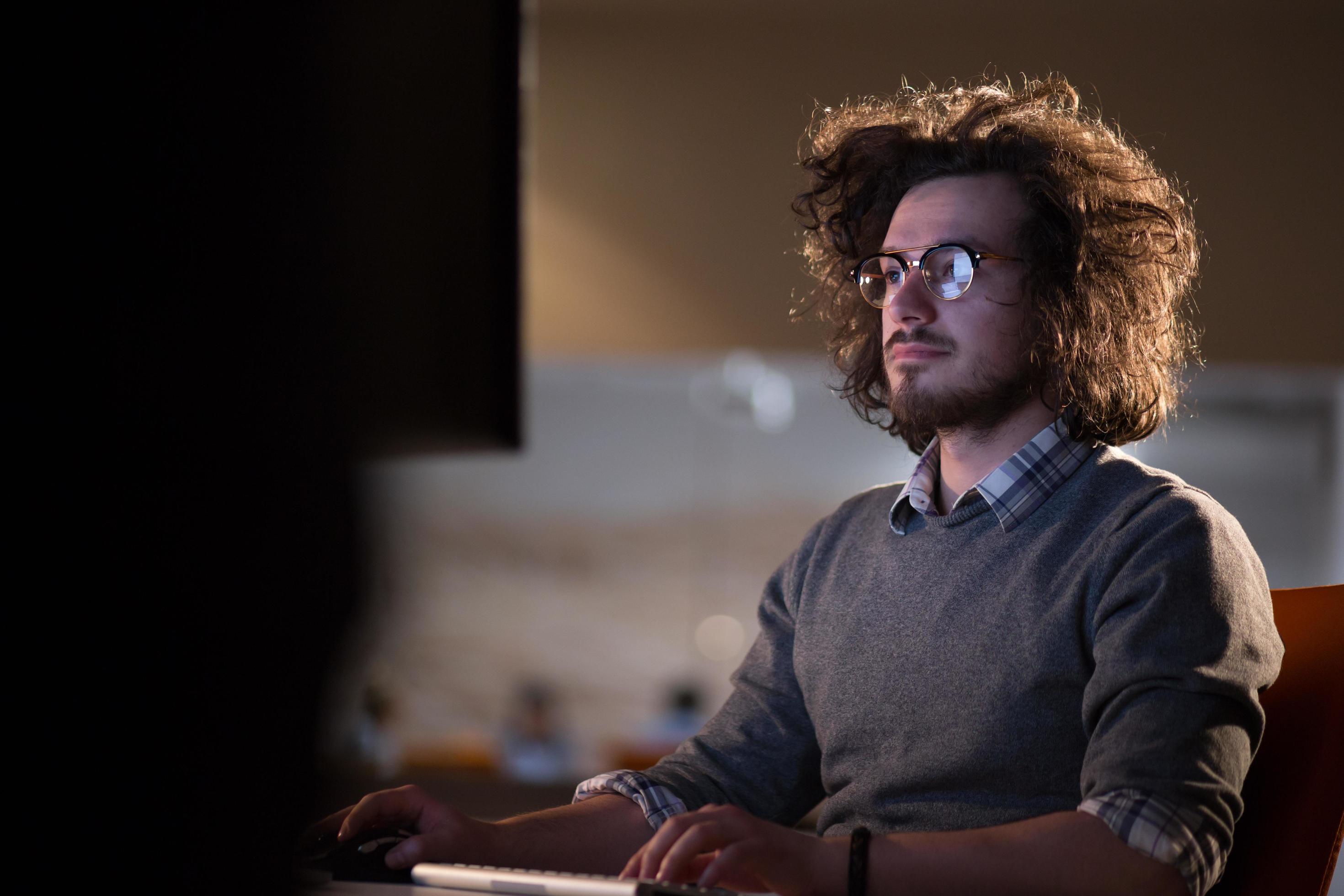 man working on computer in dark office 12435796 Stock Photo at Vecteezy