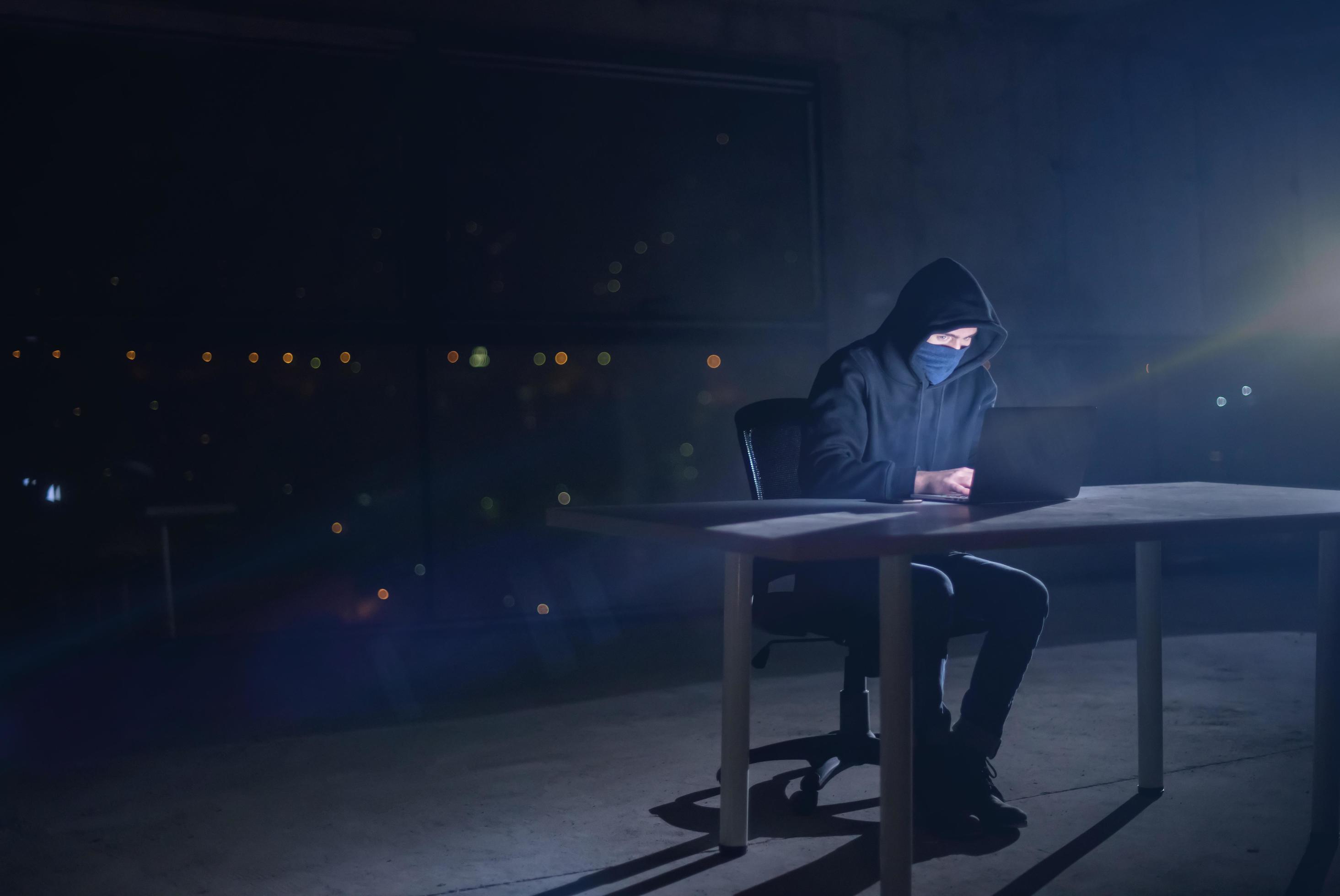hacker using laptop computer while working in dark office 12445933 ...