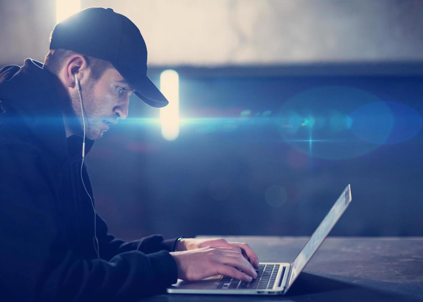 Young Talented Hacker Using Laptop Computer While Working In Dark