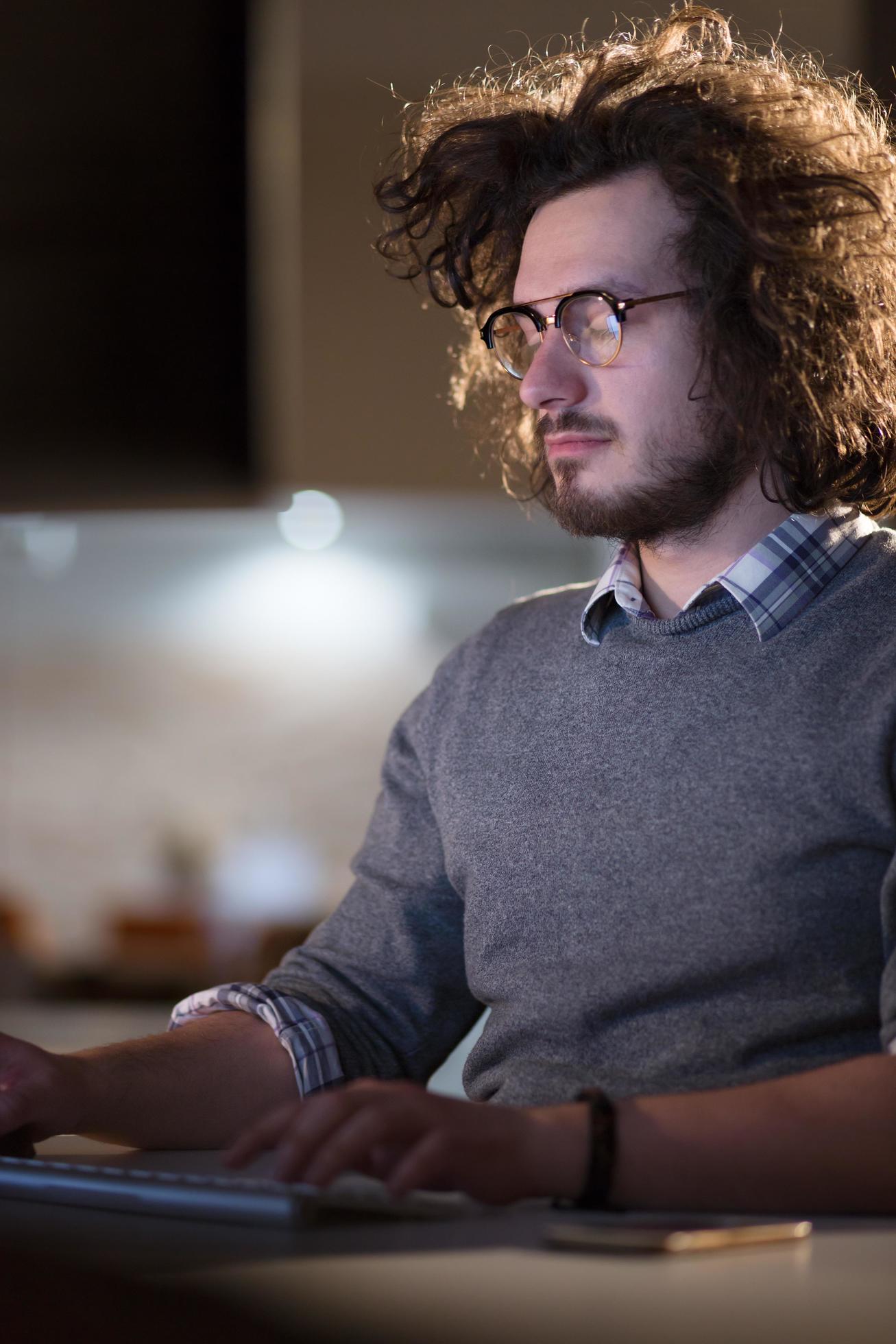 man working on computer in dark office 12449747 Stock Photo at Vecteezy