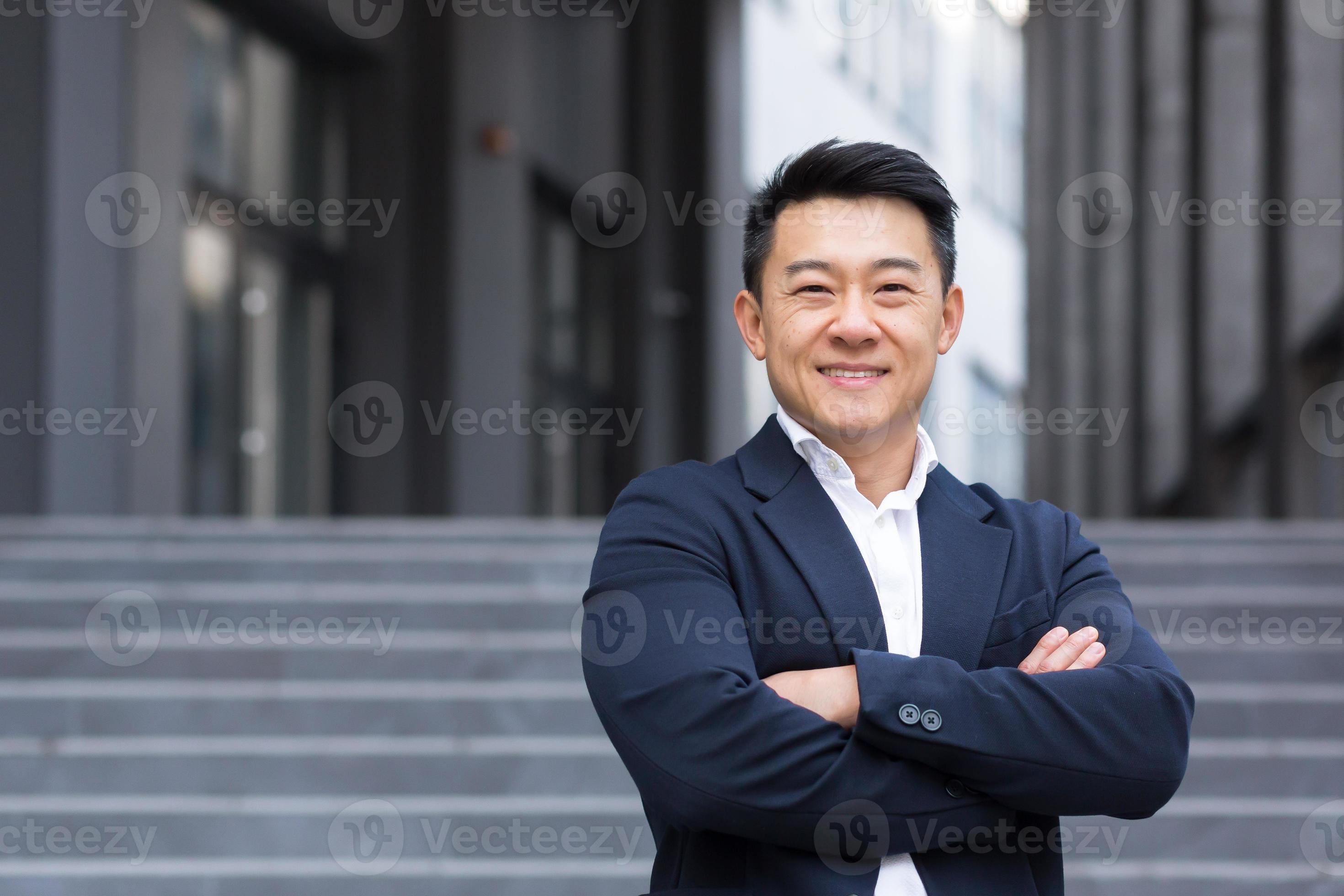 Portrait of Asian cheerful and successful businessman near office in ...