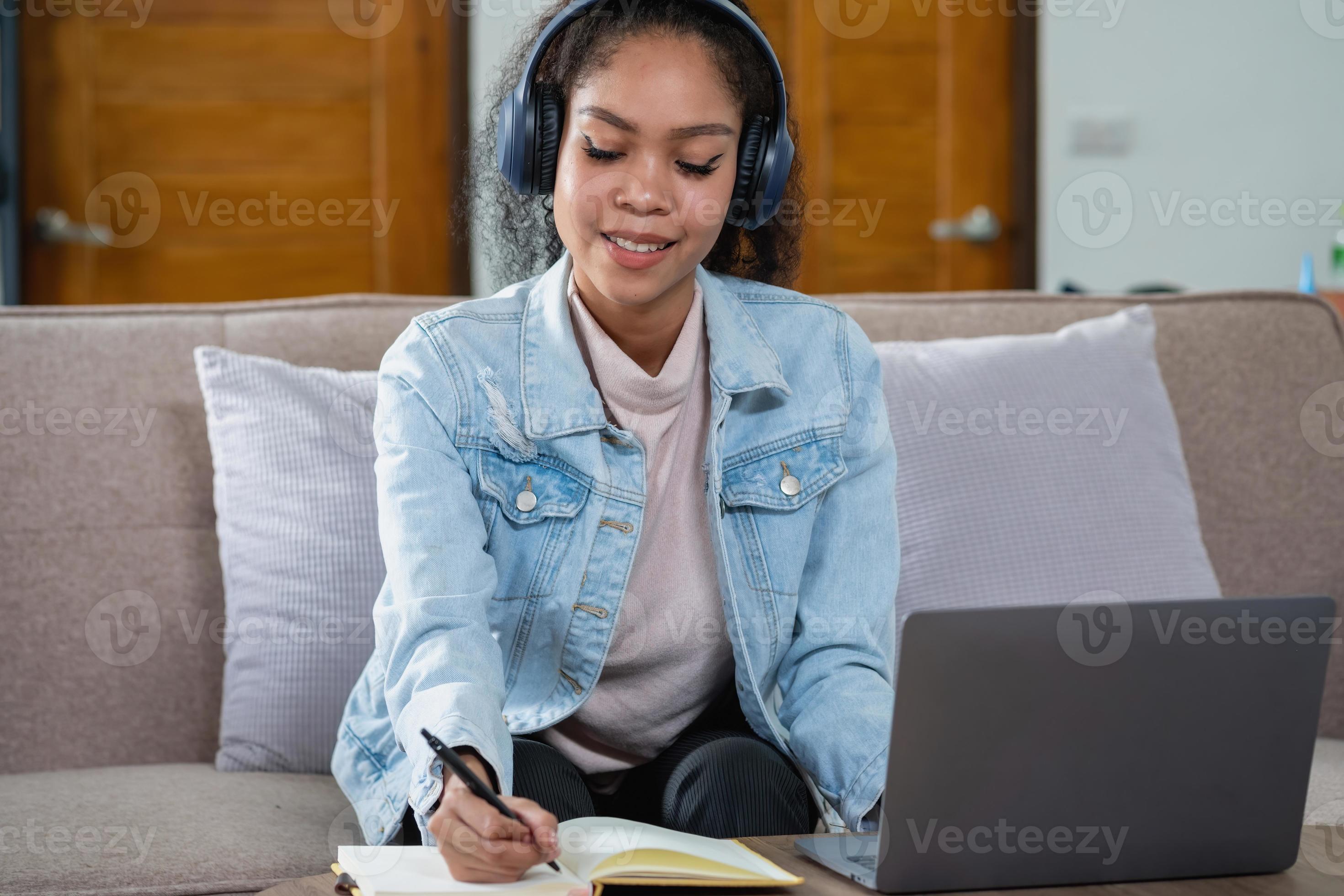 African woman, American, using laptop computer and wearing headphones ...