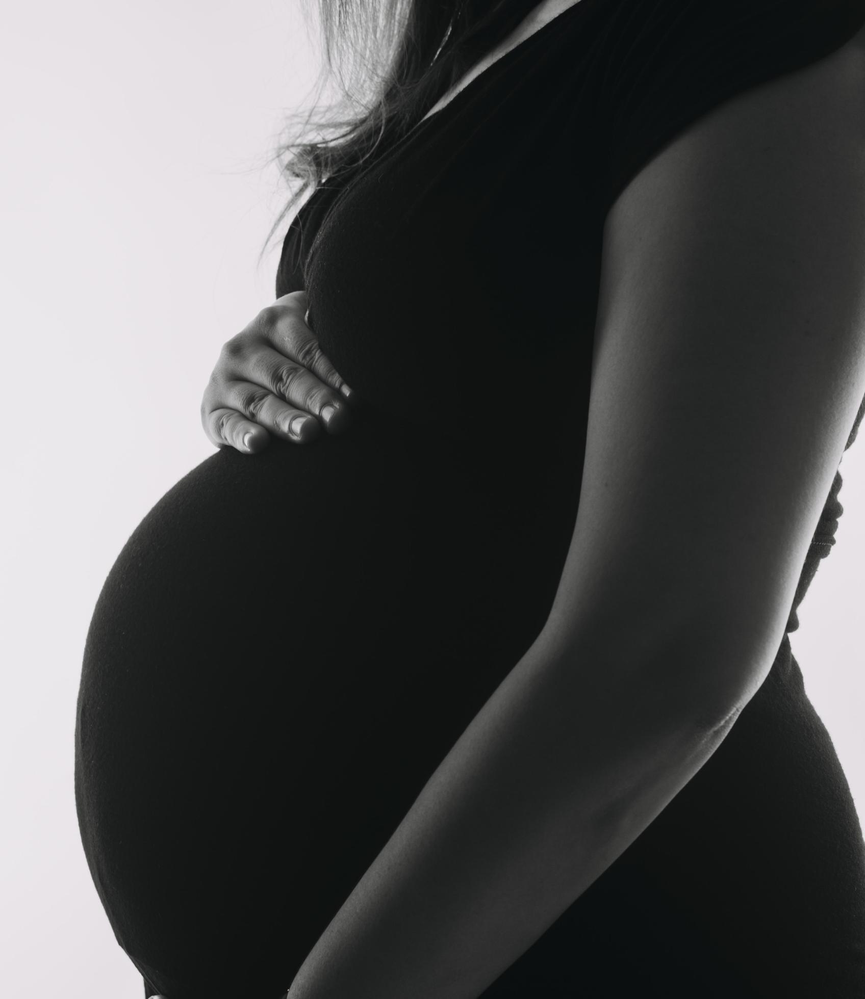 Young Adult Pregnant Woman In White Clothes Touching Big Naked Belly