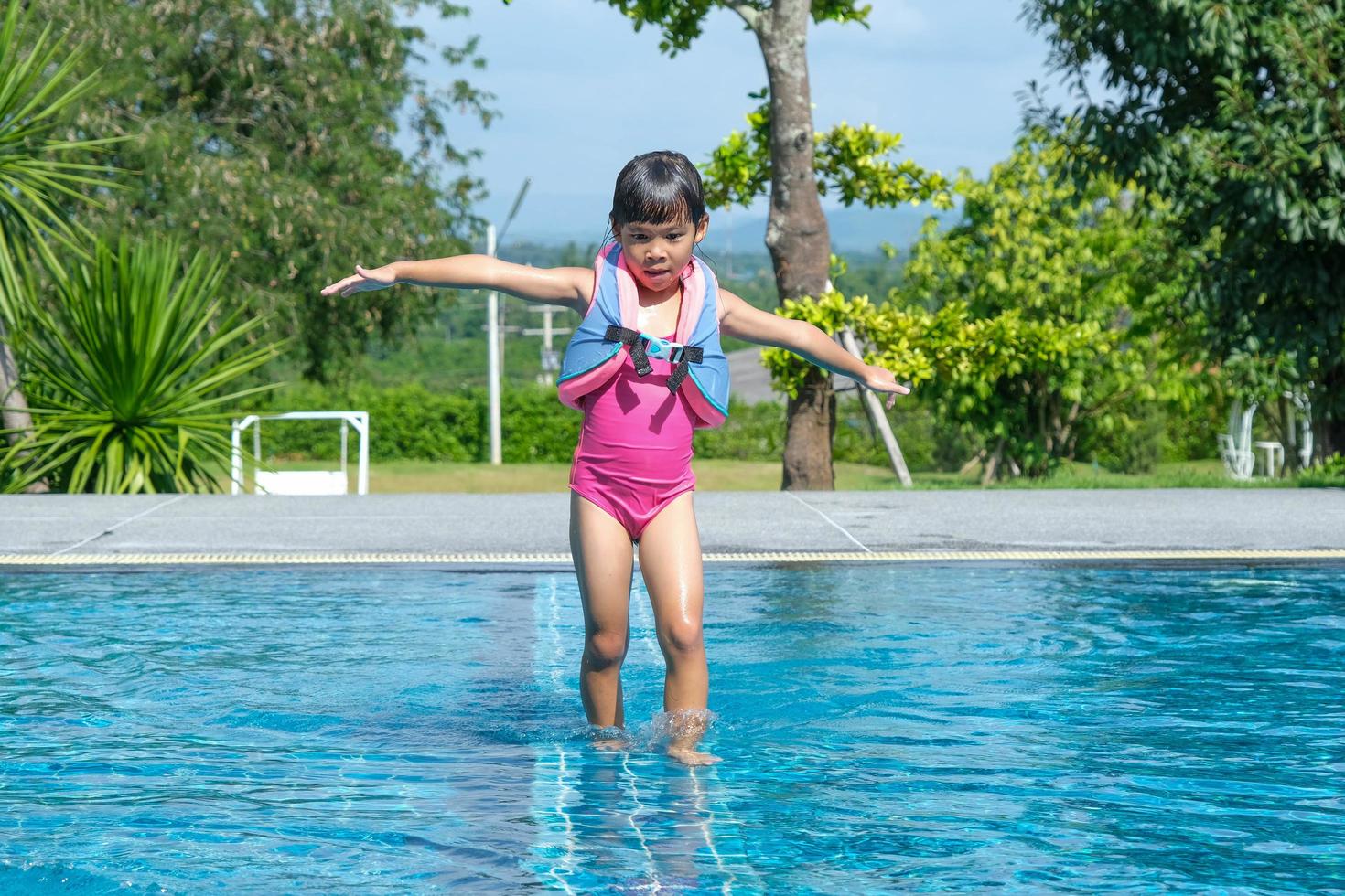 Happy little sisters play in outdoor swimming pool of tropical resort during family summer ...