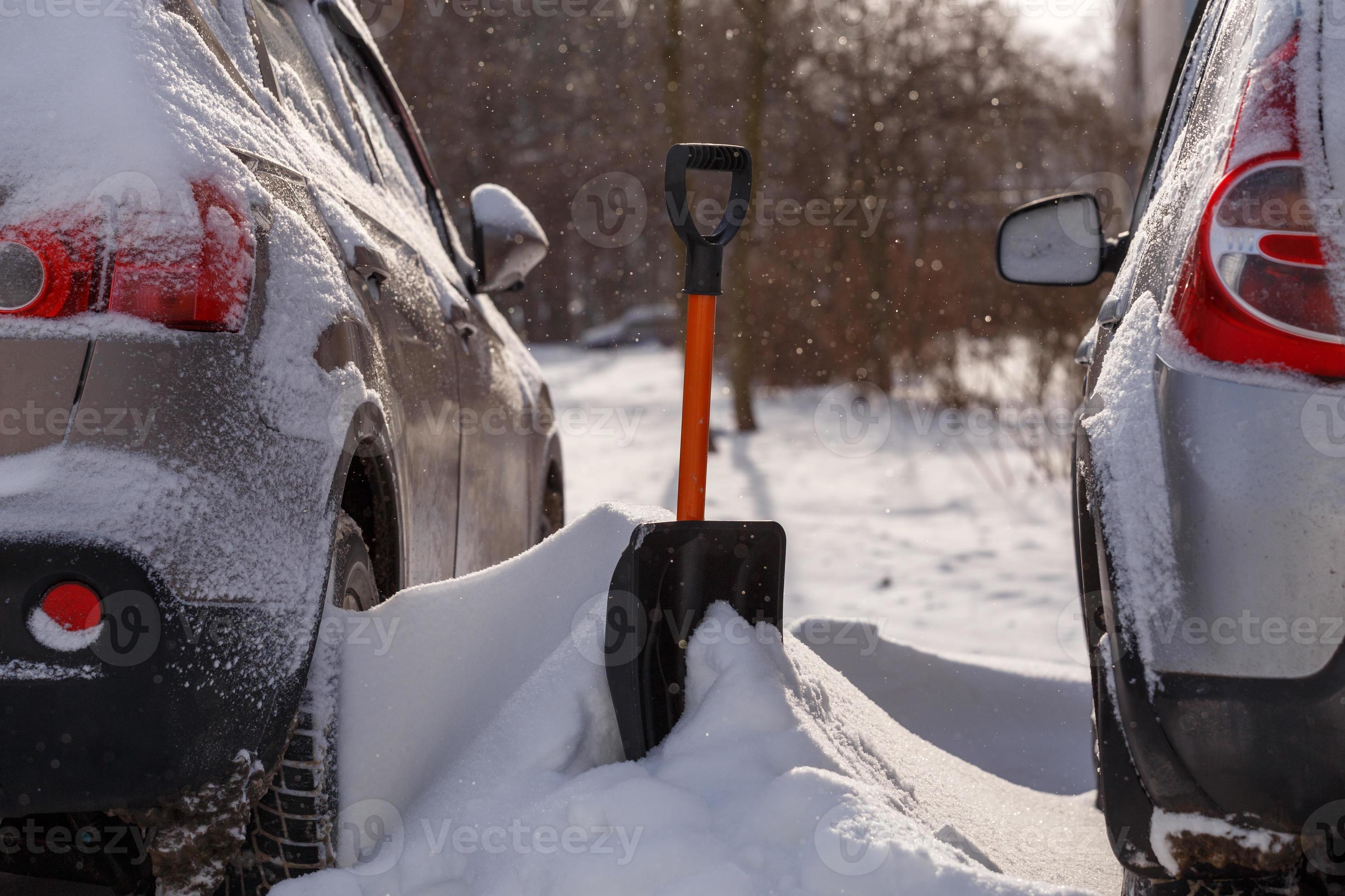 small plastic shovel sticking out from a snowdrift between two cars in ...