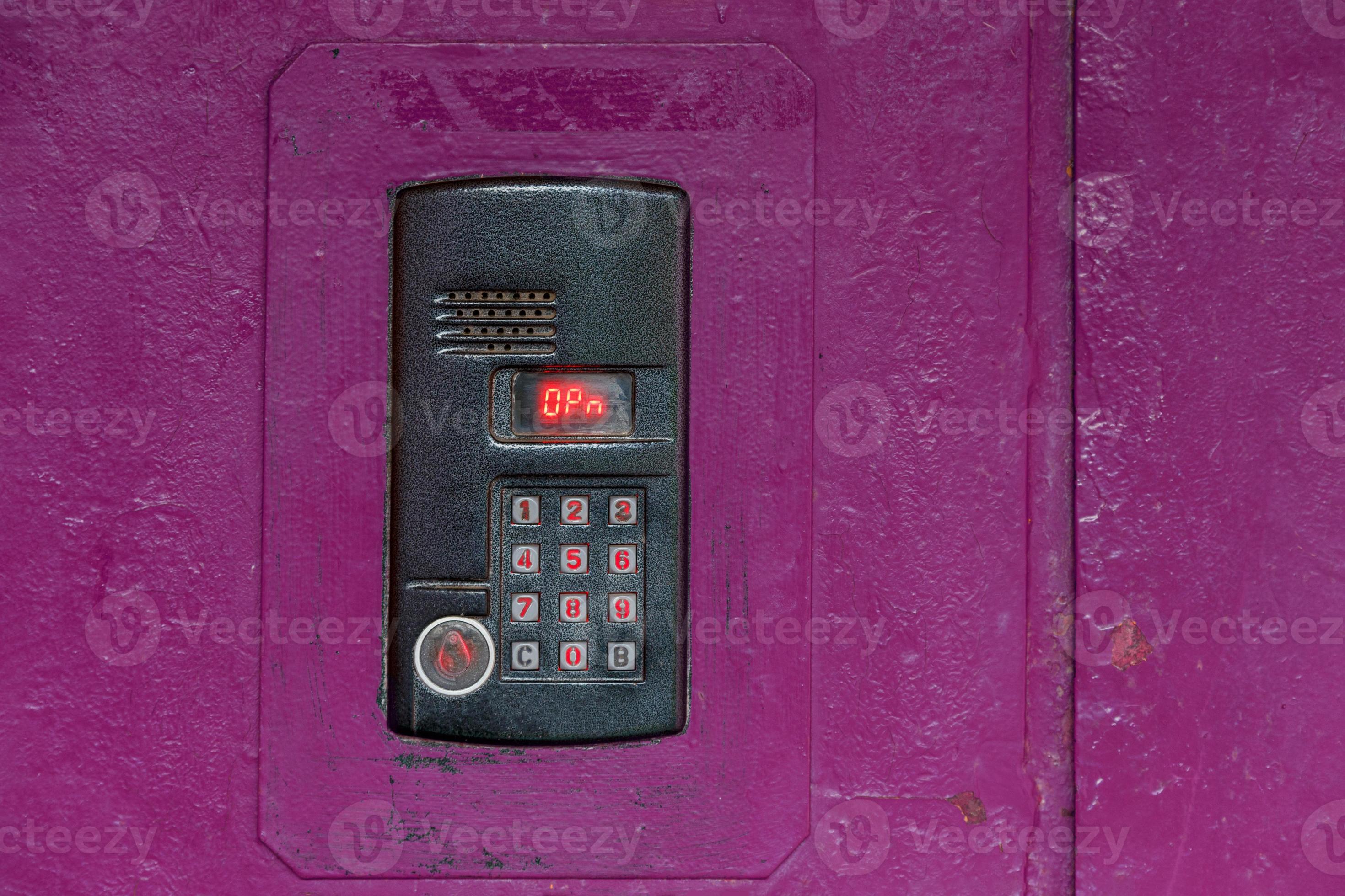 An intercom on old painted pink steel surface with a keypad, digital ...