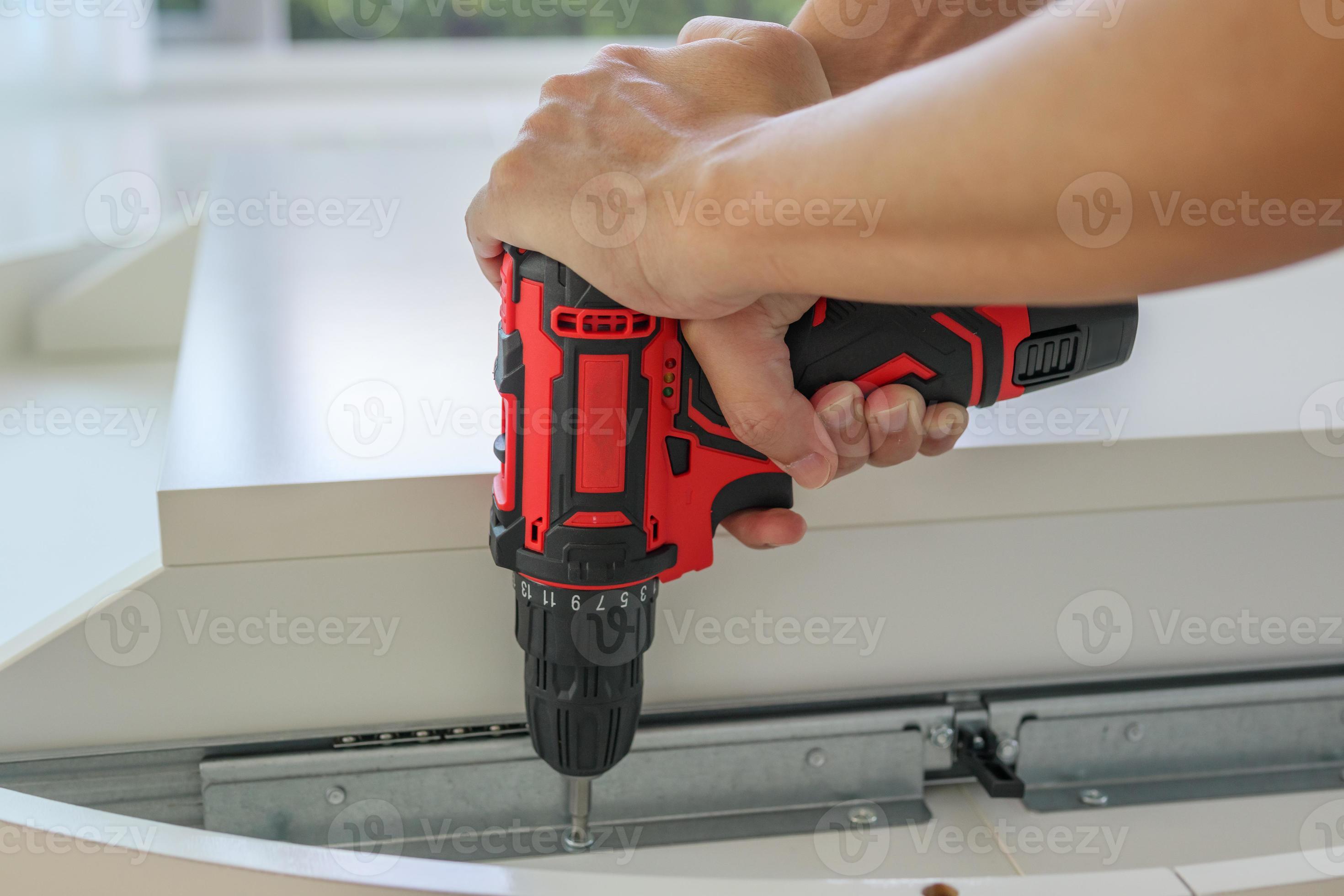 Man Assembling White Table Furniture At Home Using Cordless Screwdriver
