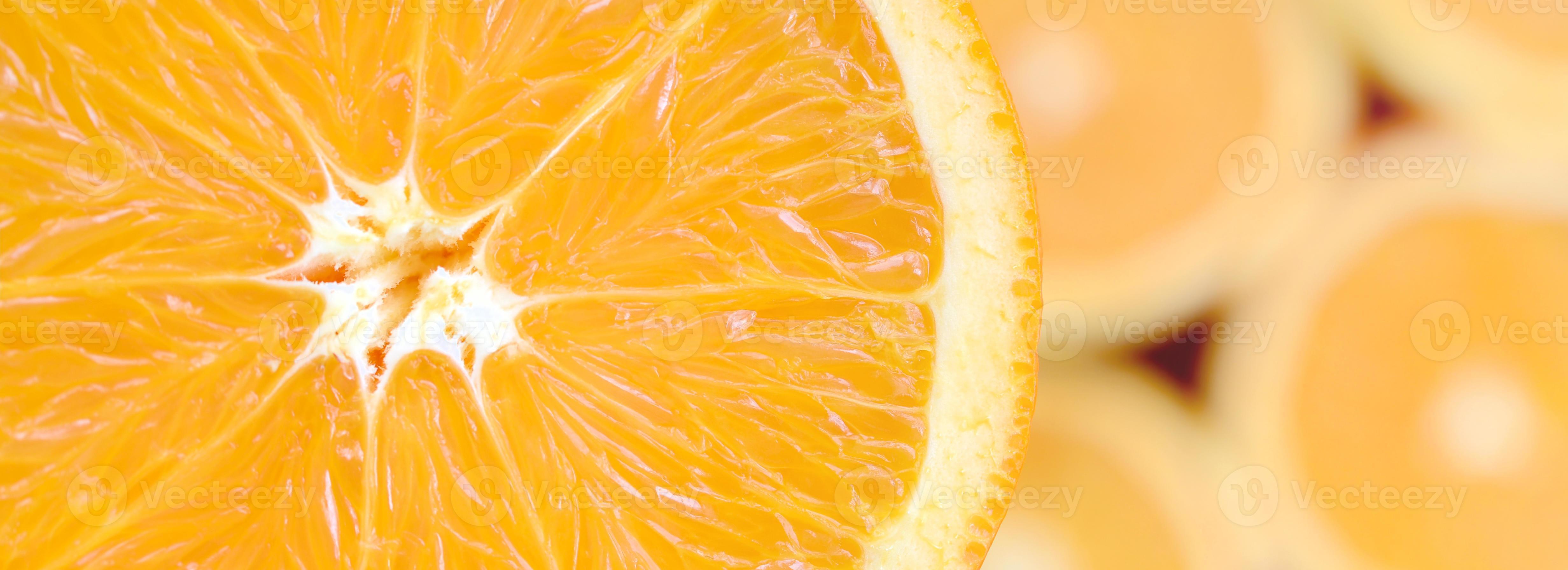 Top view of a fragment of the orange fruit slice on the background of many blurred orange slices ...