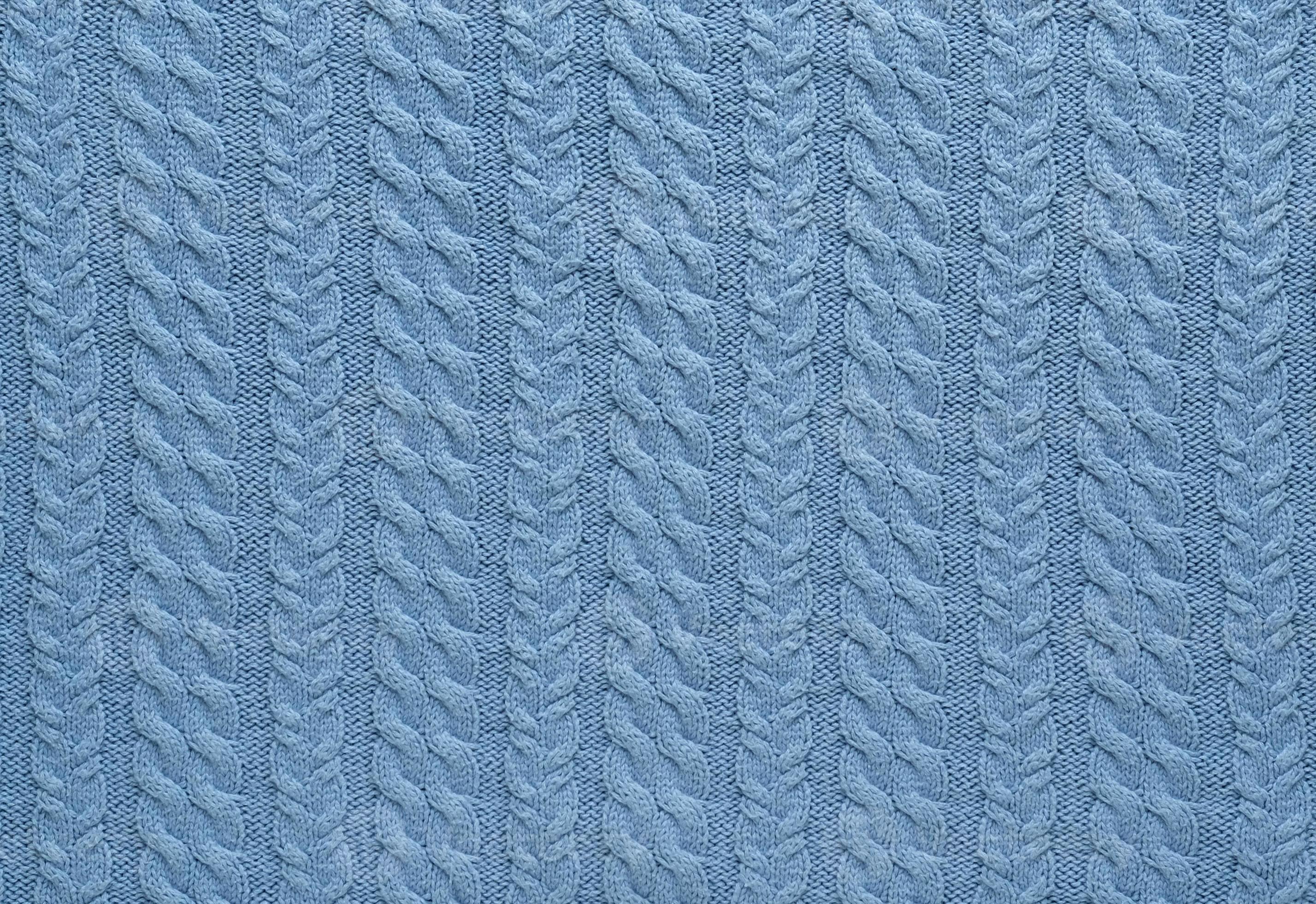 Texture of smooth knitted blue sweater with pattern. Top view, close-up. Handmade knitting wool ...