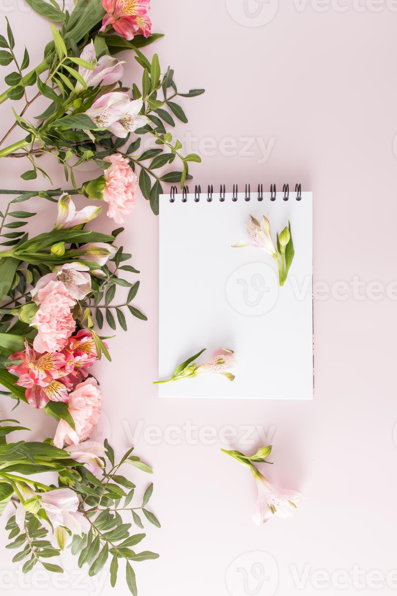 vertical top view of the blank white sheets of the notebook. pink pastel background with spring ...