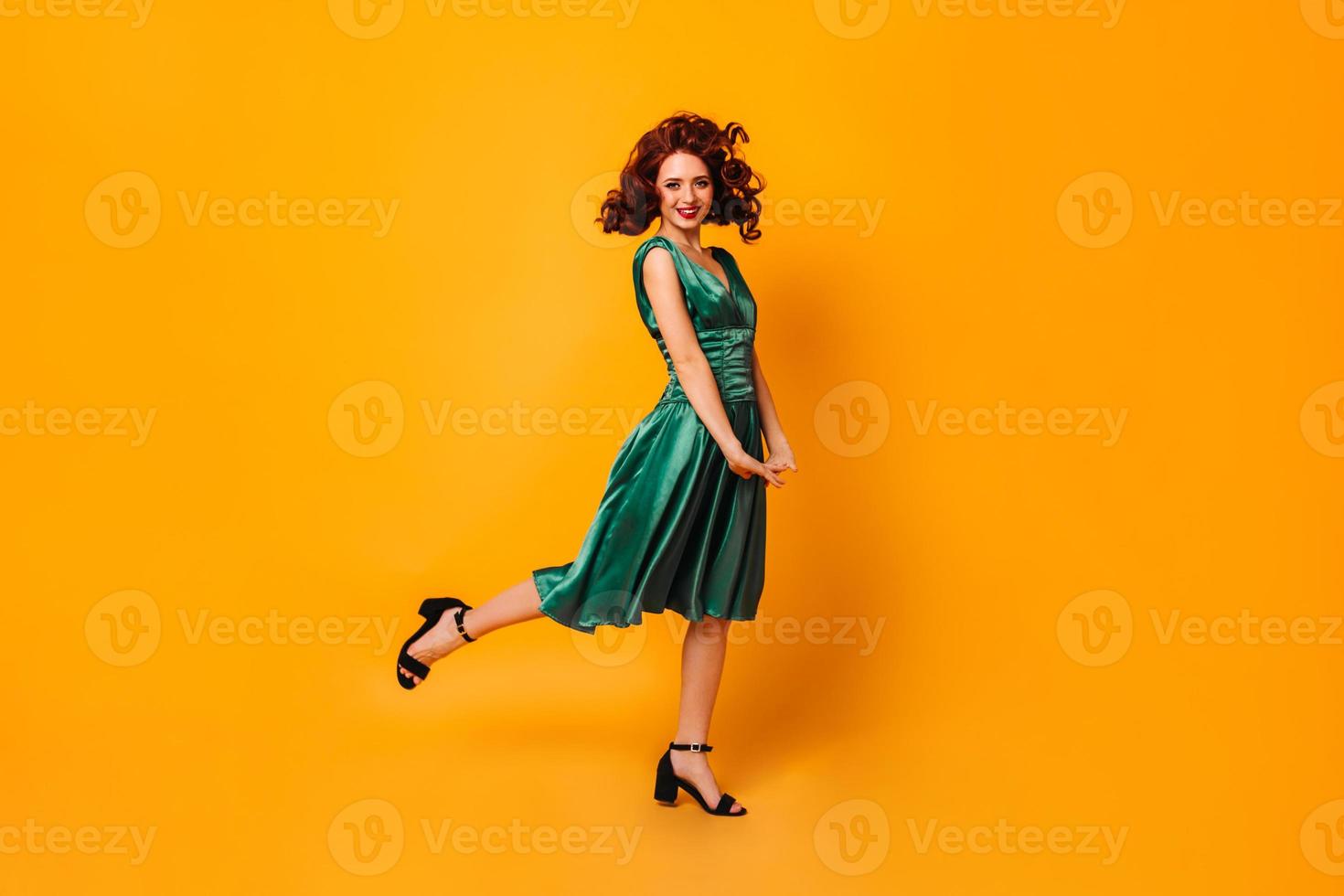 Excited Fit Girl In Green Dress Standing On One Leg Full Length View