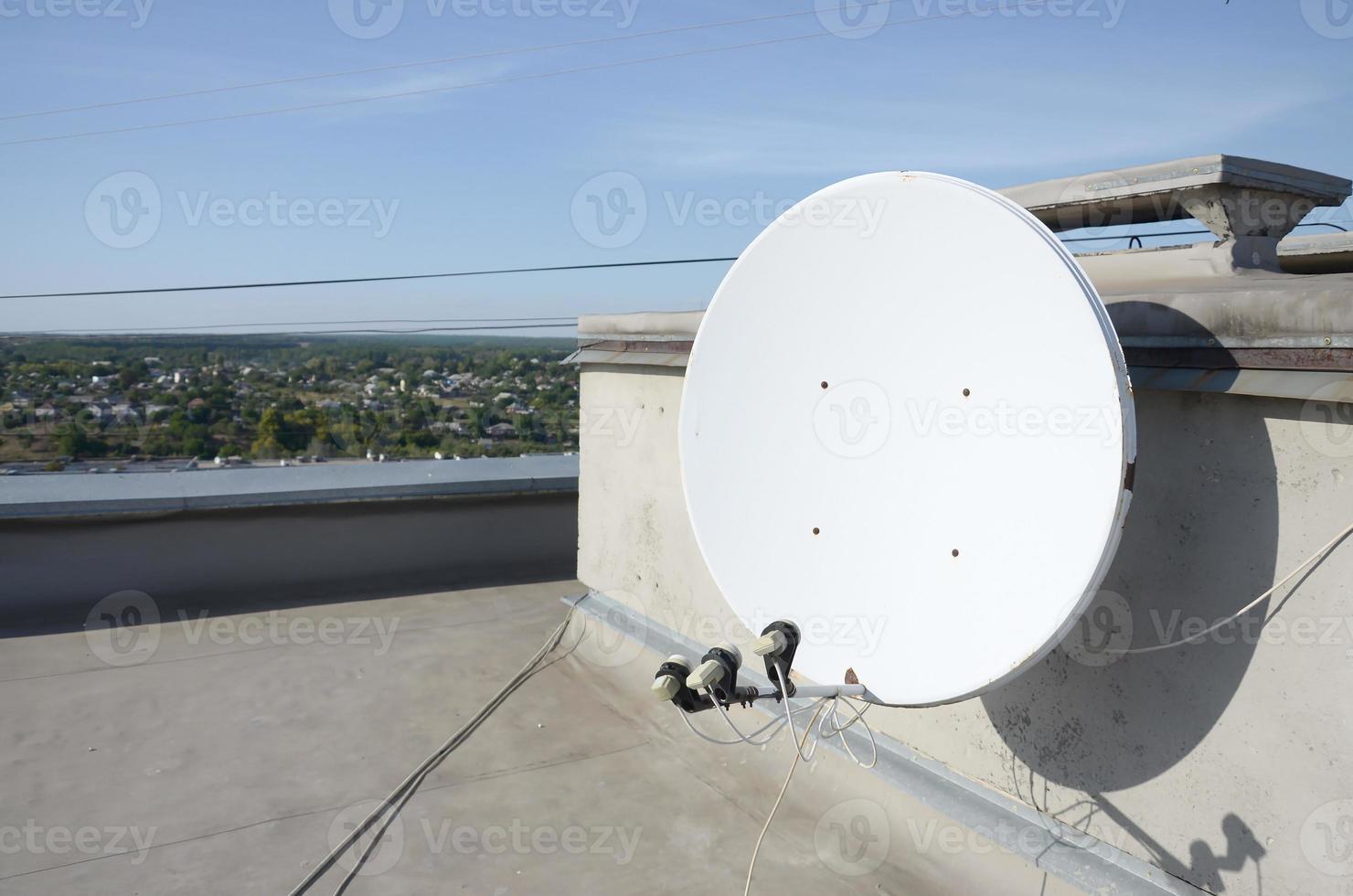 White satellite dish with three converters mounted on residental ...