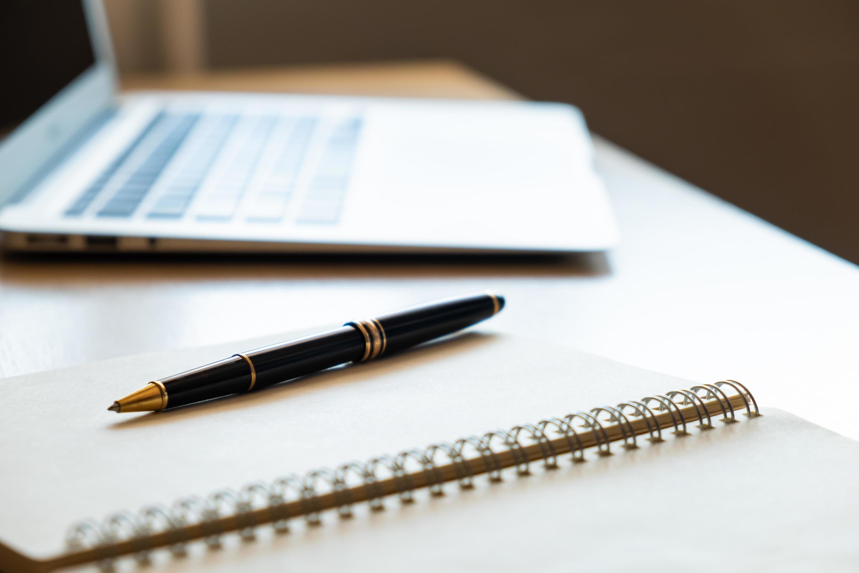 Selective focus at pen on plain notebook paper on working table. With ... Selective focus at pen on plain notebook paper on working table. With ...