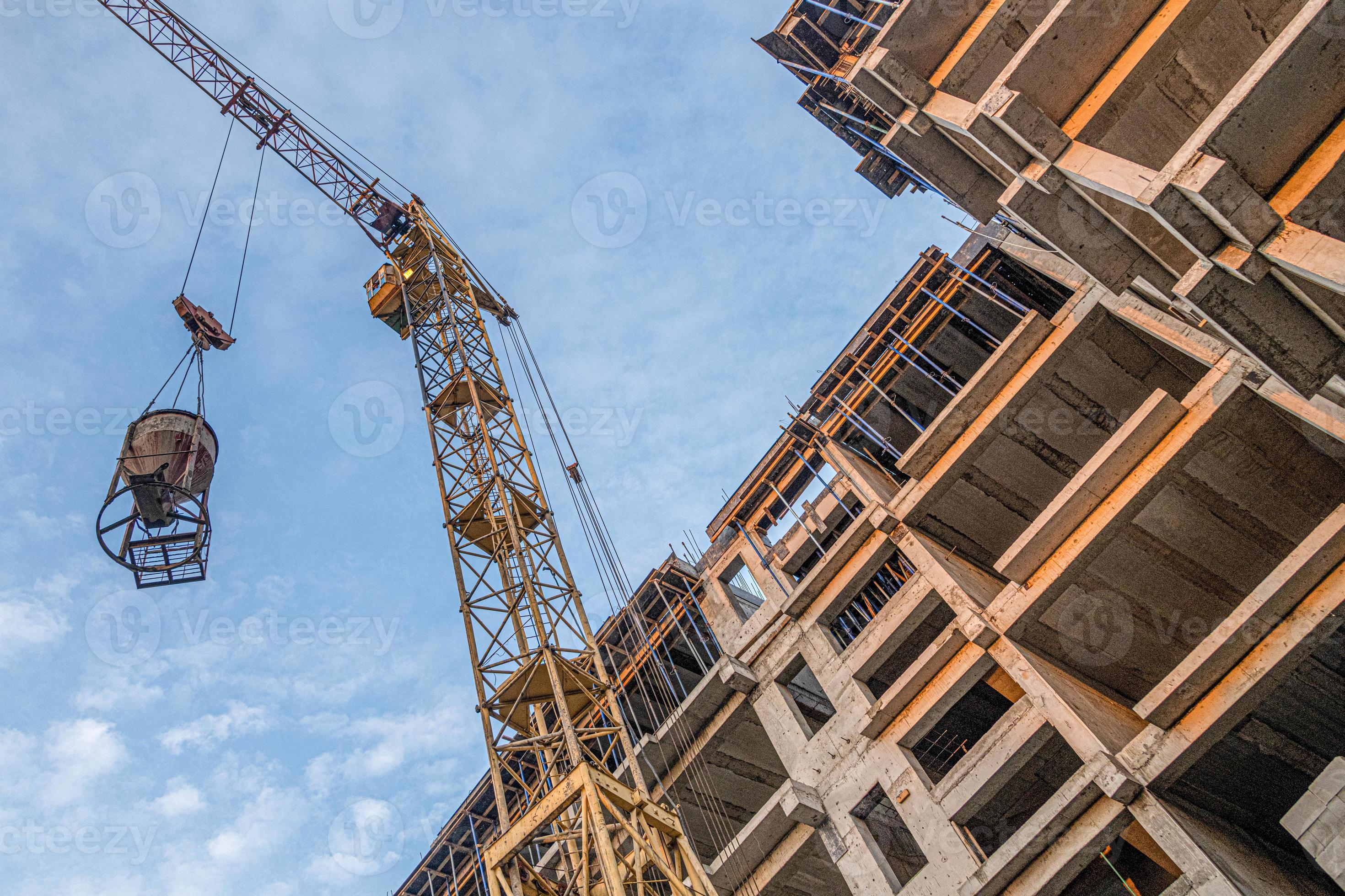 A low angle shot of a crane with equipment on a construction site with a new building ...