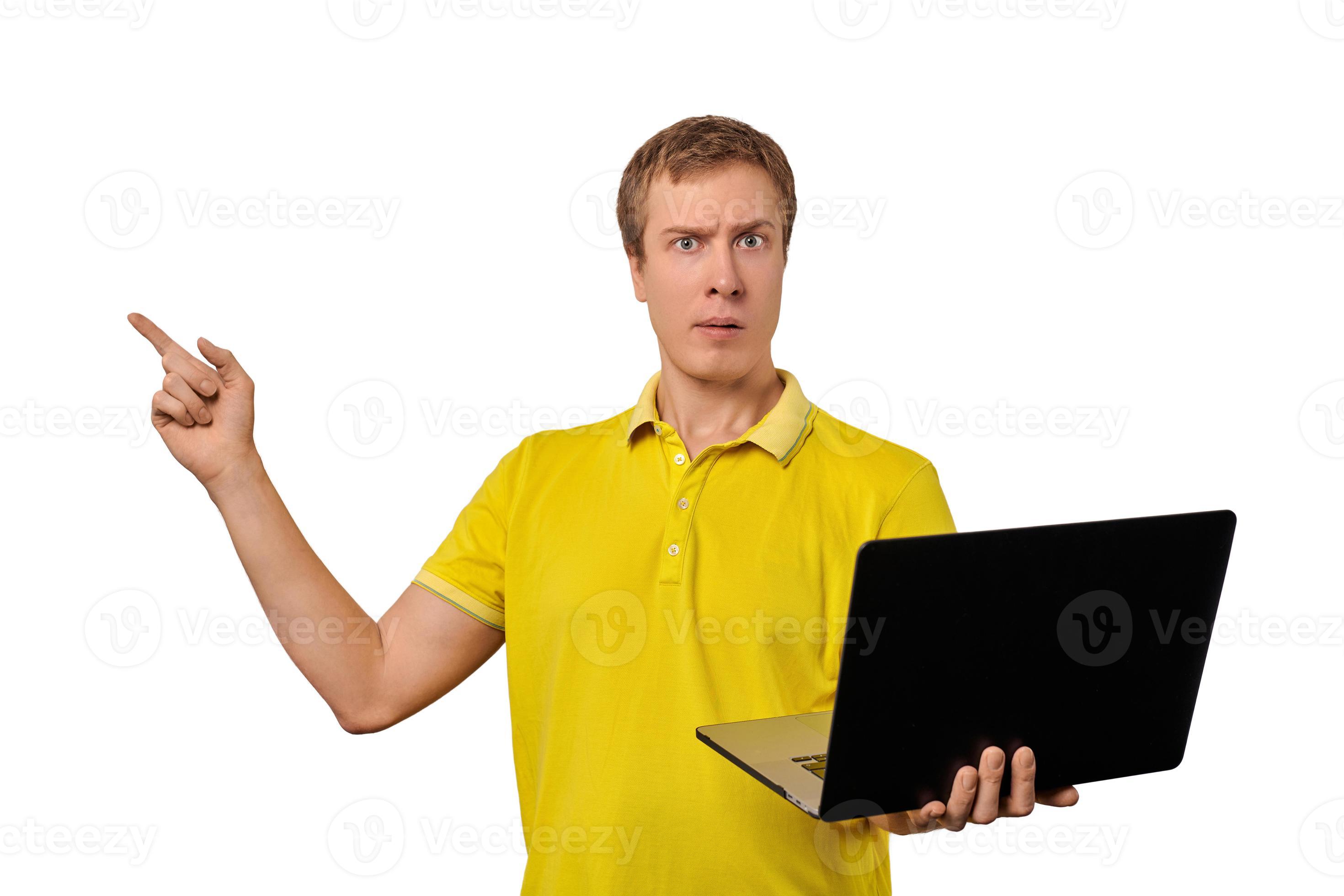 Puzzled young man with laptop pointing with finger isolated on white ...