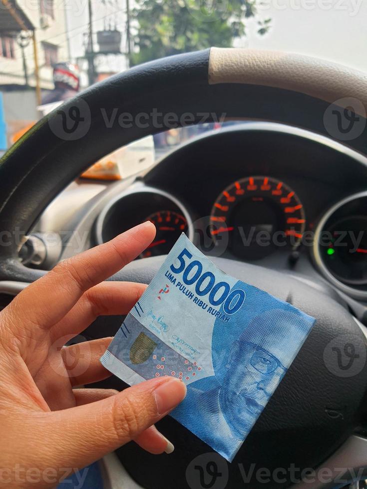 A hand is holding a fifty thousand rupiah bill which bends while ...