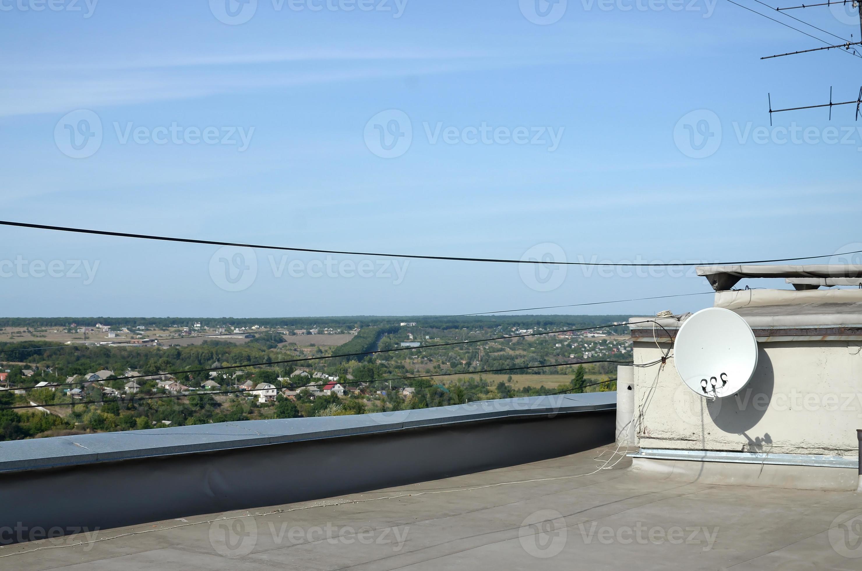 White satellite dish with three converters mounted on residental ...