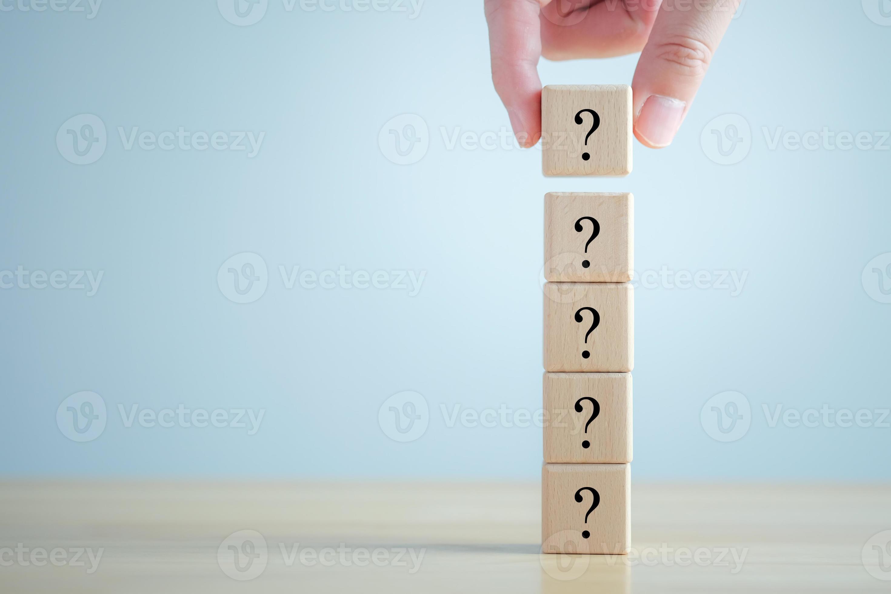 Hand holding question mark symbol from stack of wooden block with copy space. Ask, FAQ, Advice ...