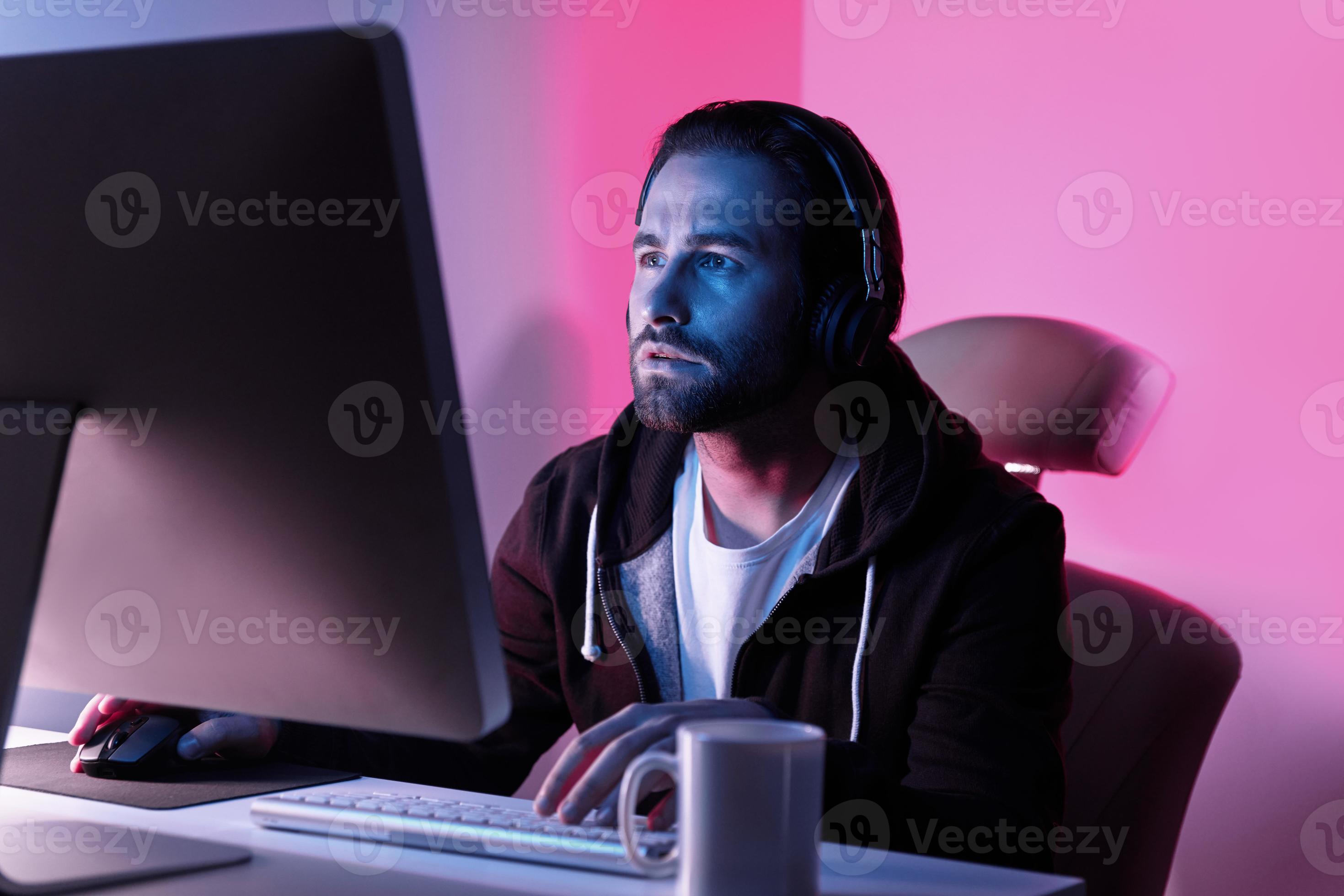 Concentrated young man looking at the computer monitor while sitting ...