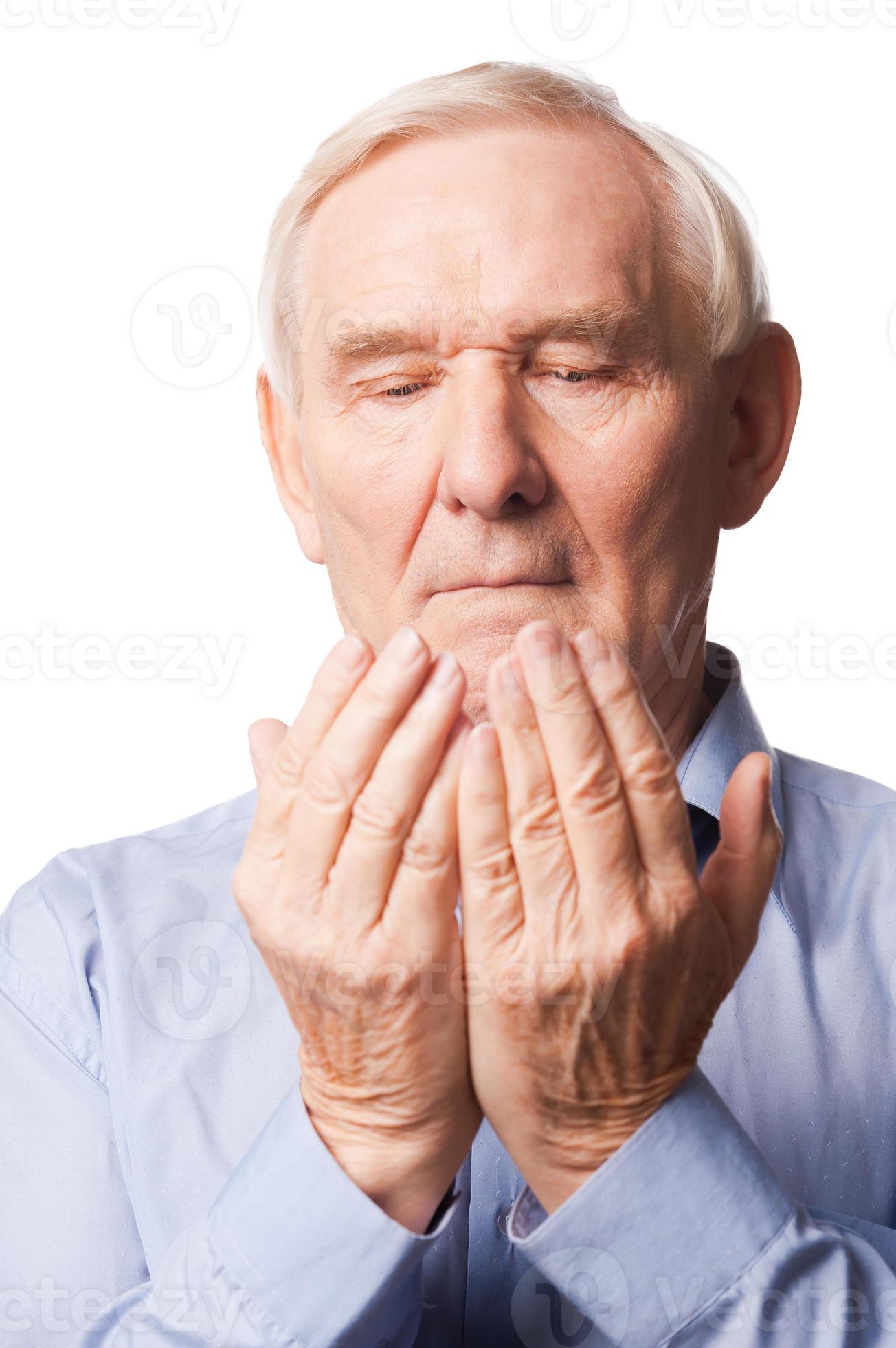 Thoughtful senior. Portrait of senior man looking at his palms while ...