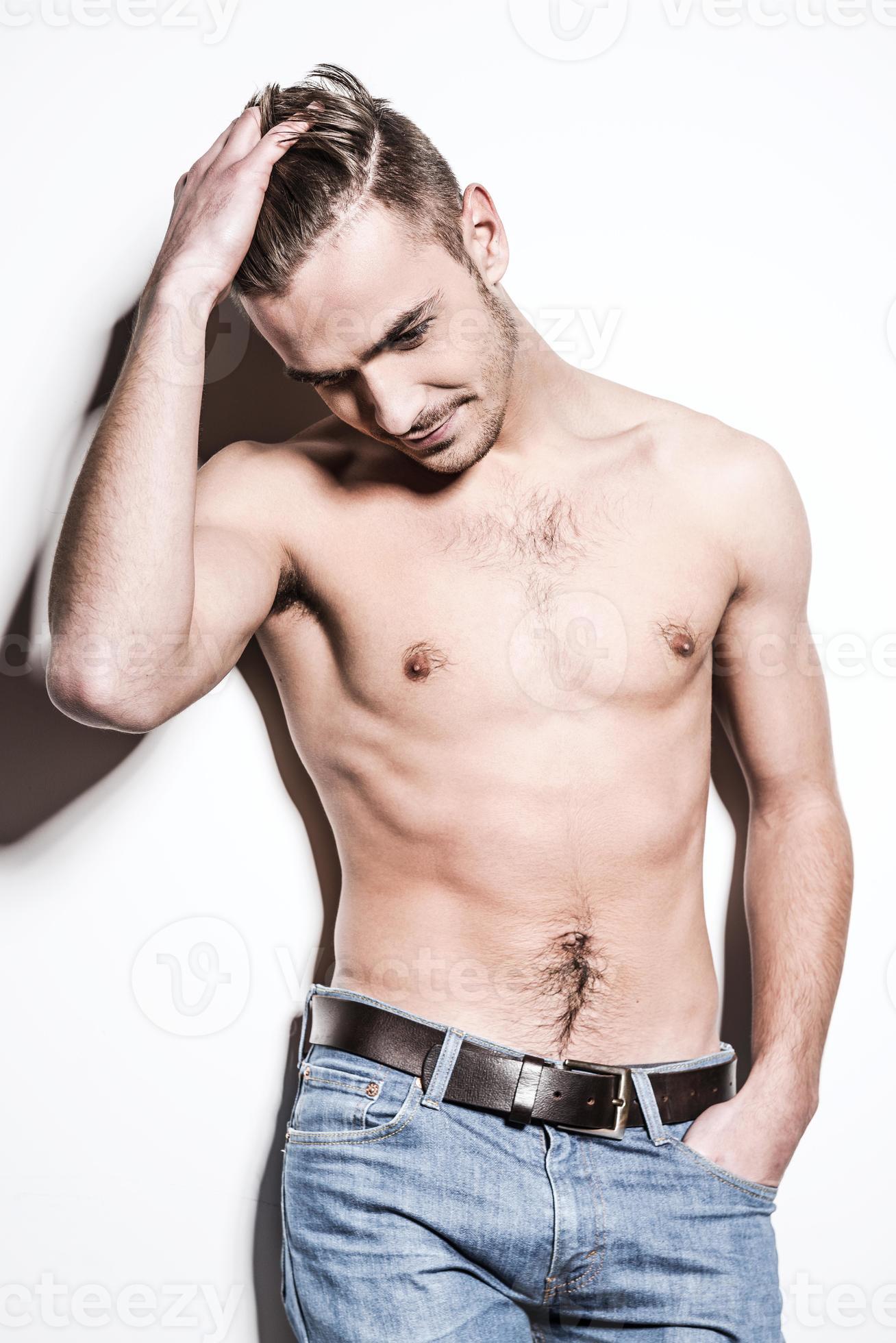 Charming handsome. Handsome young shirtless man in jeans holding hand ...