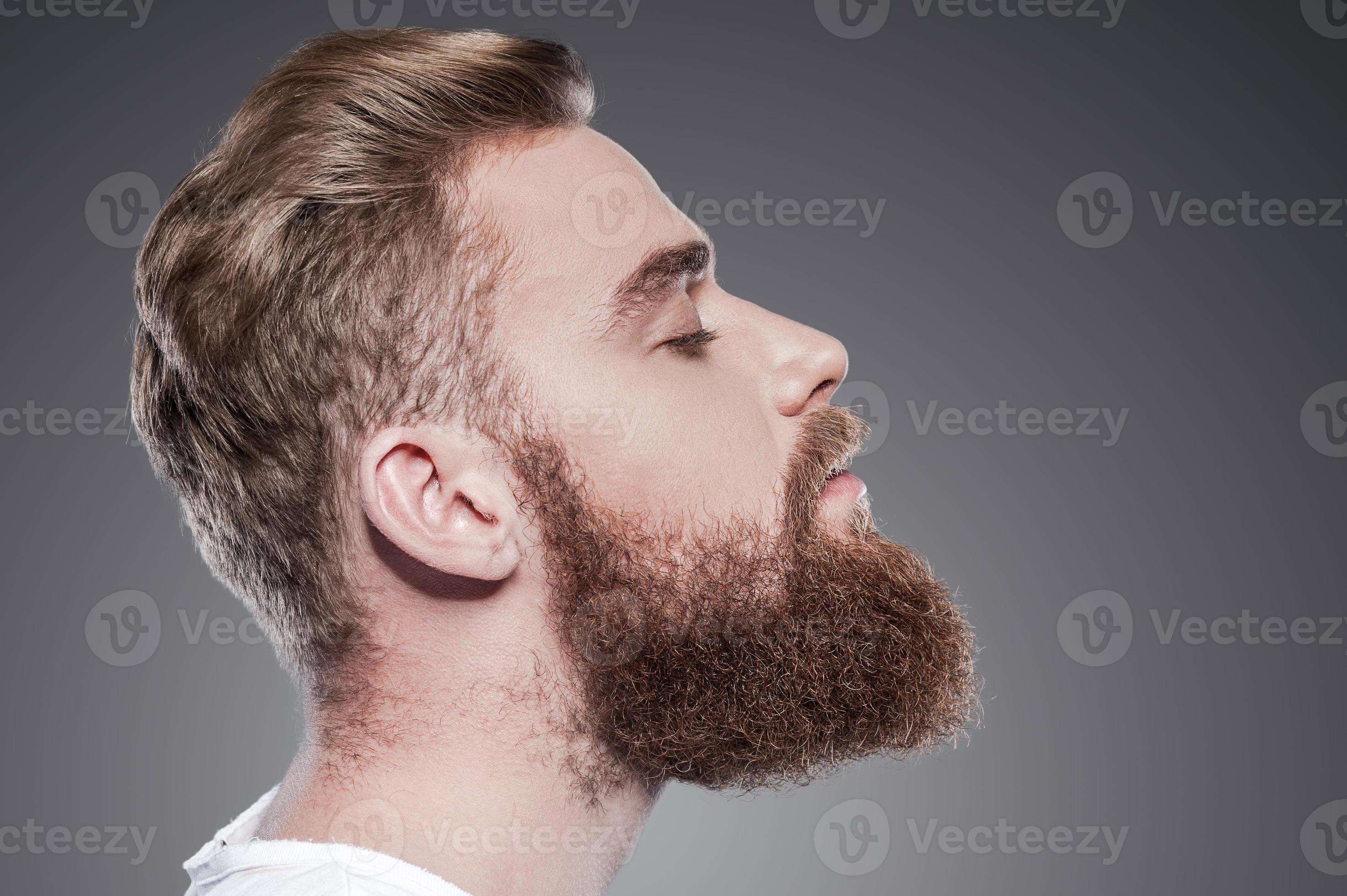 Bearded handsome. Side view of handsome young bearded man keeping eyes ...