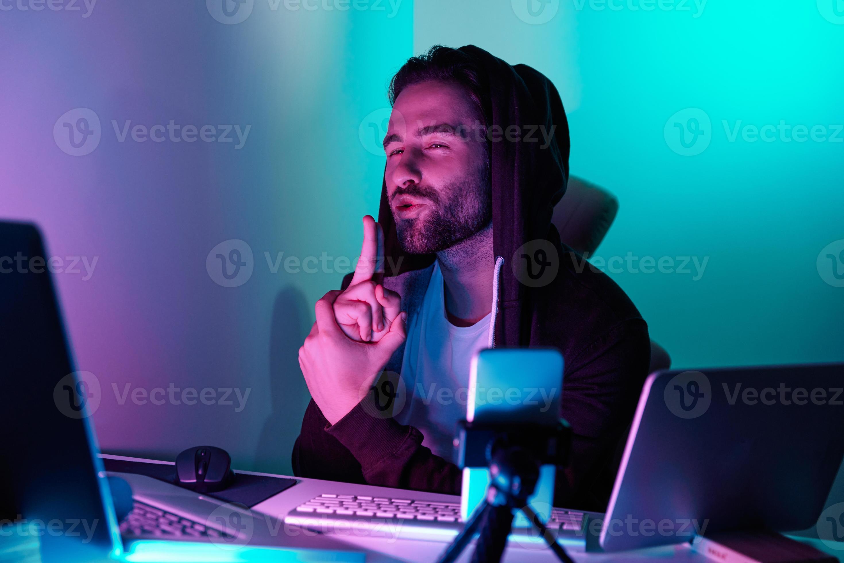 Playful young man looking at the computer monitor and gesturing gun ...