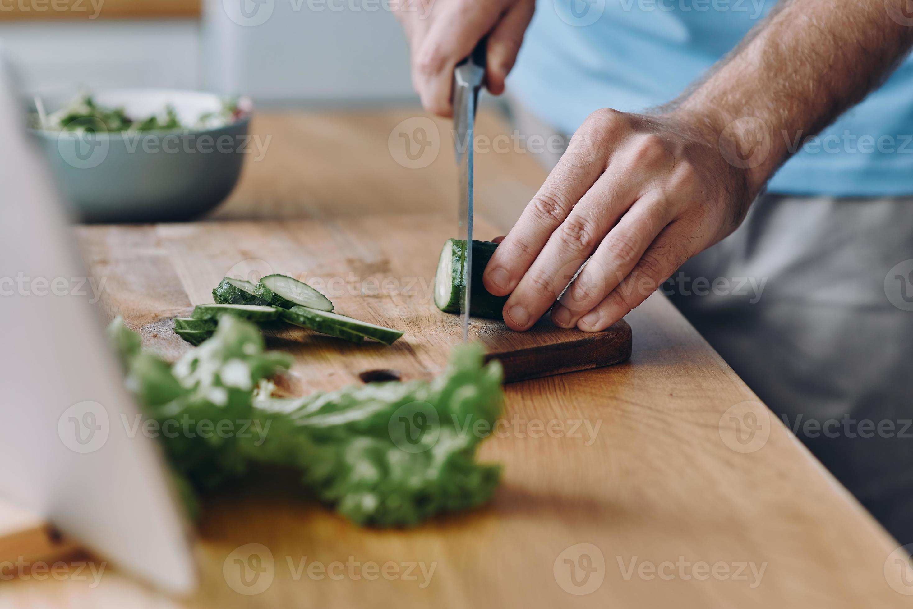 Close-up of unrecognizable man cutting vegetables while standing at the ... Close-up of unrecognizable man cutting vegetables while standing at the ...
