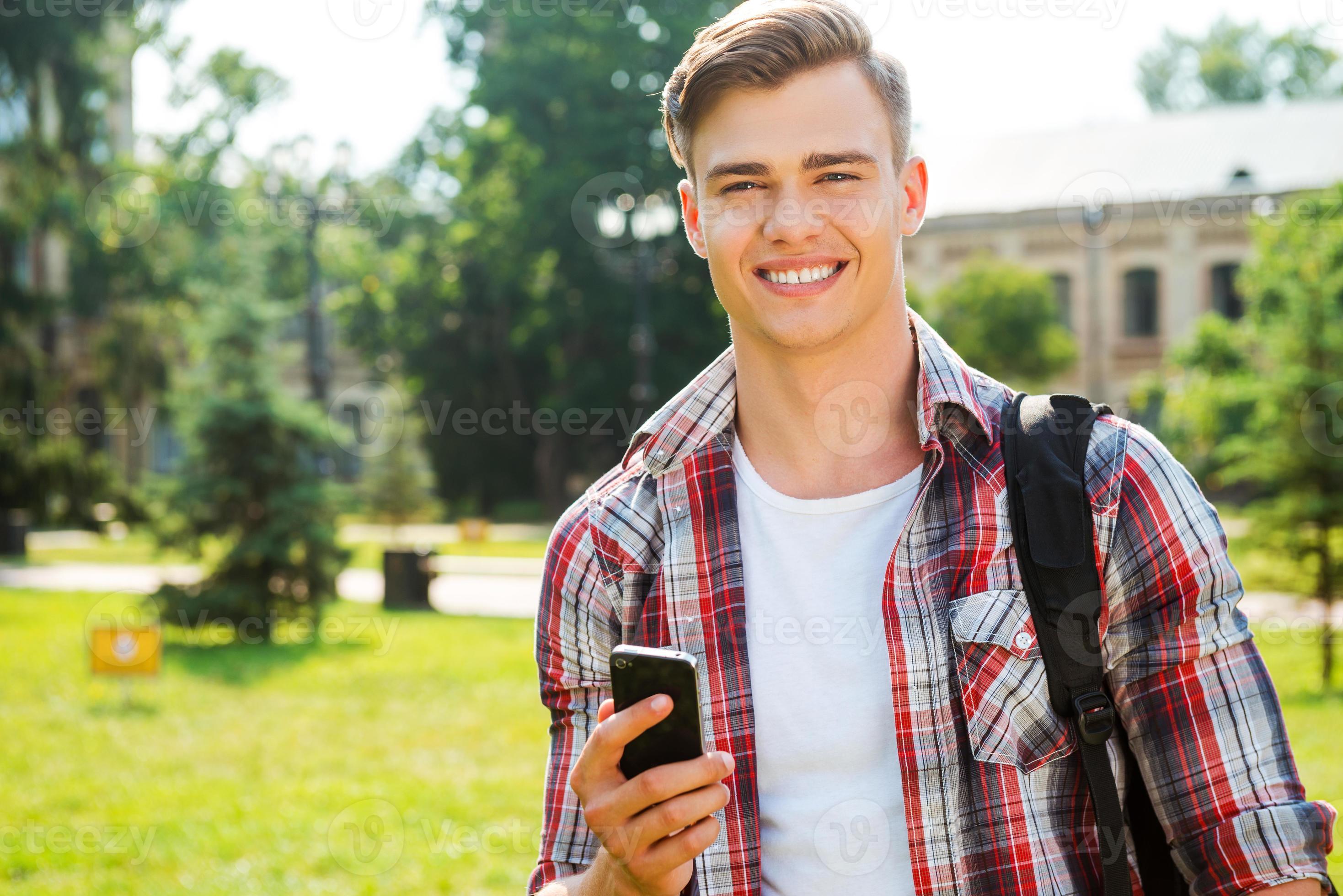 Confident and successful student. Handsome male student holding mobile ...
