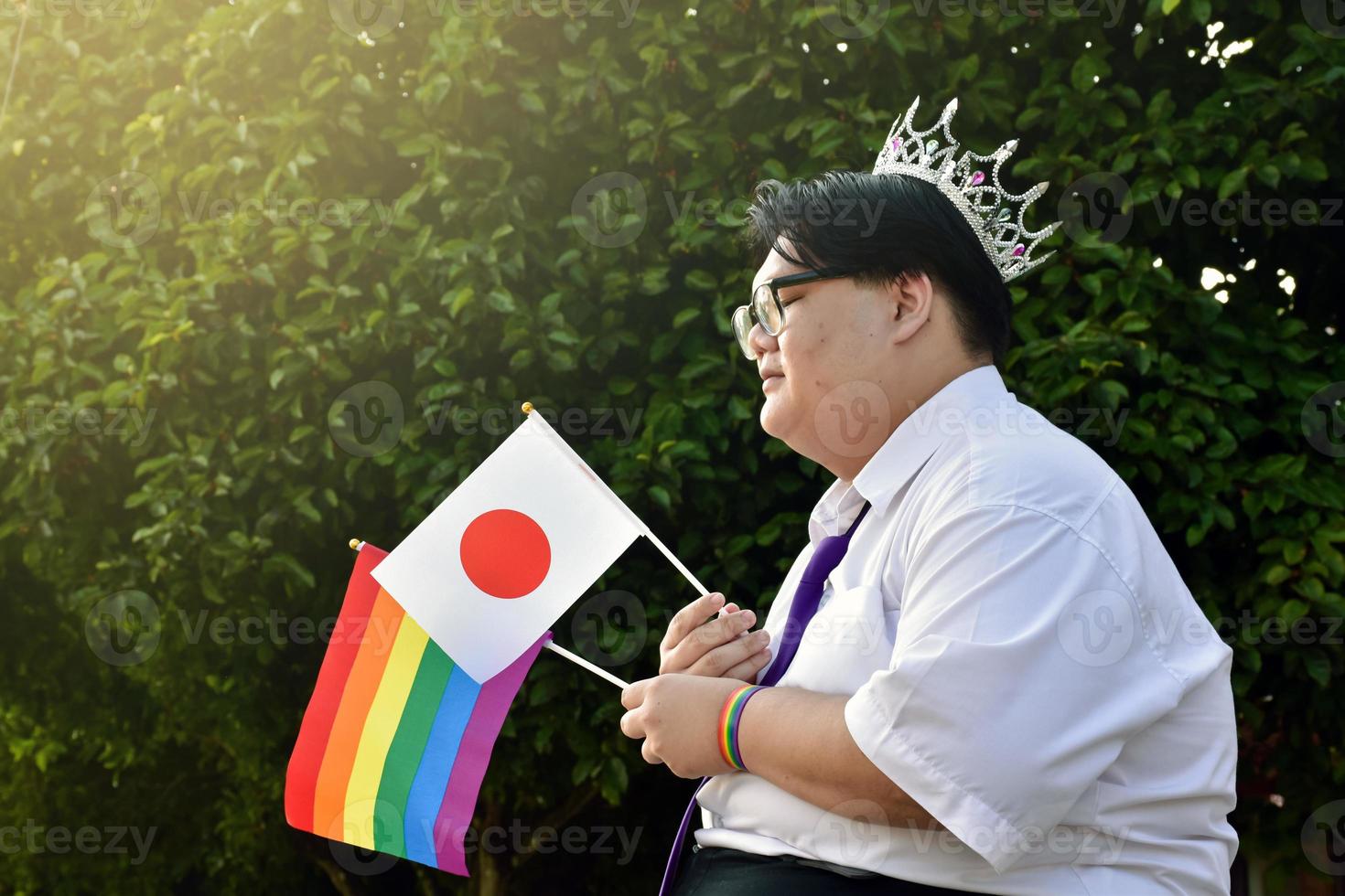 Japanese boy holds rainbow flag and Japan national flag and wears crown and violet neck tie and ...