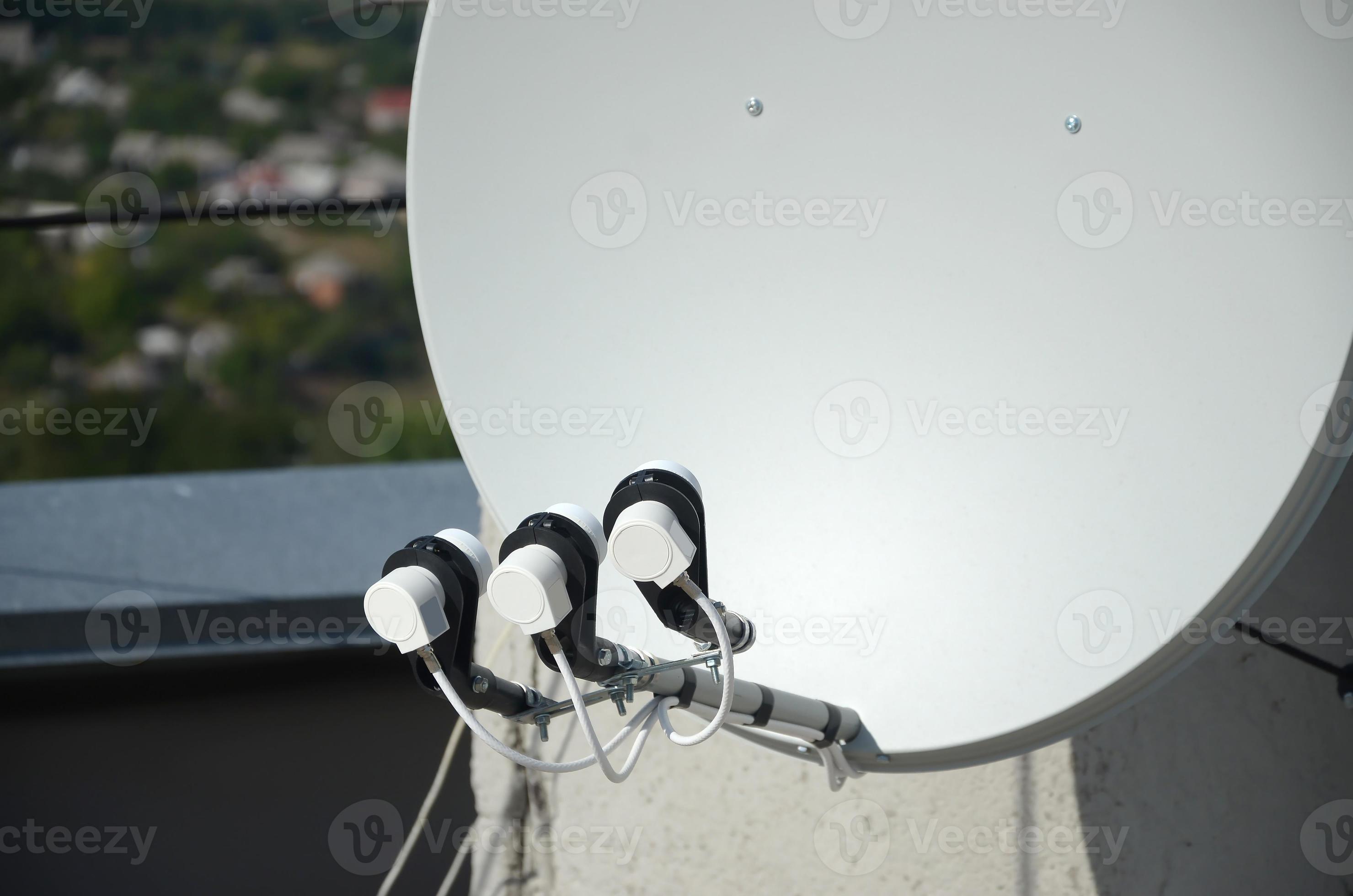 White satellite dish with three converters mounted on residental ...